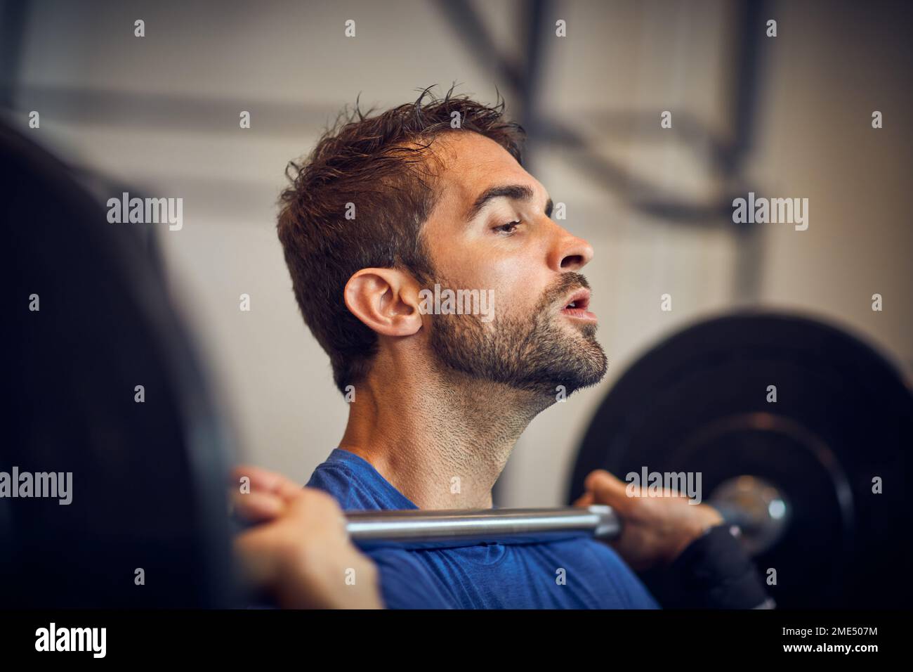 Feeling the burn. a handsome young man lifting weights while working ...