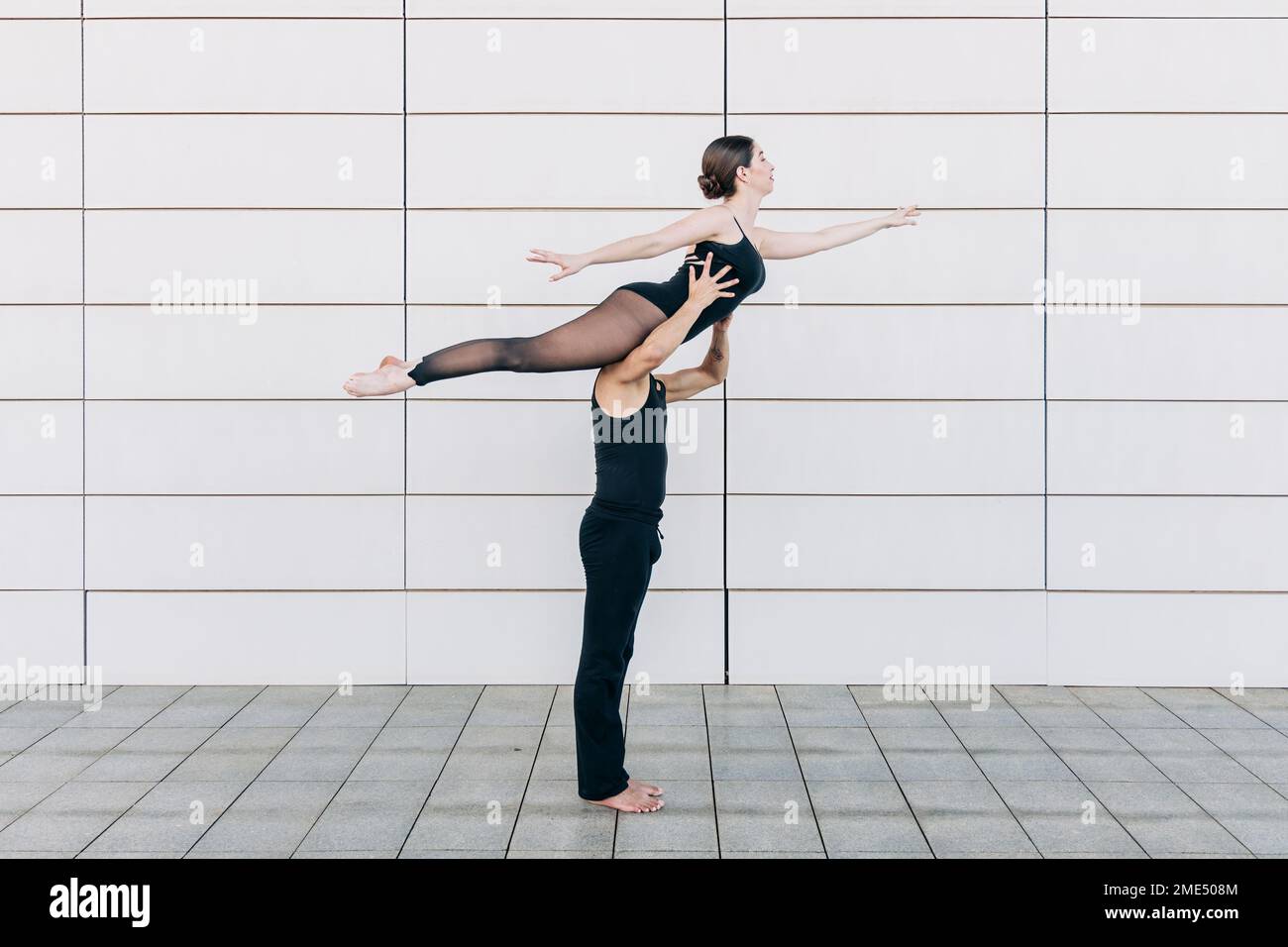 Man lifting woman practicing ballet dance in front of wall Stock Photo ...