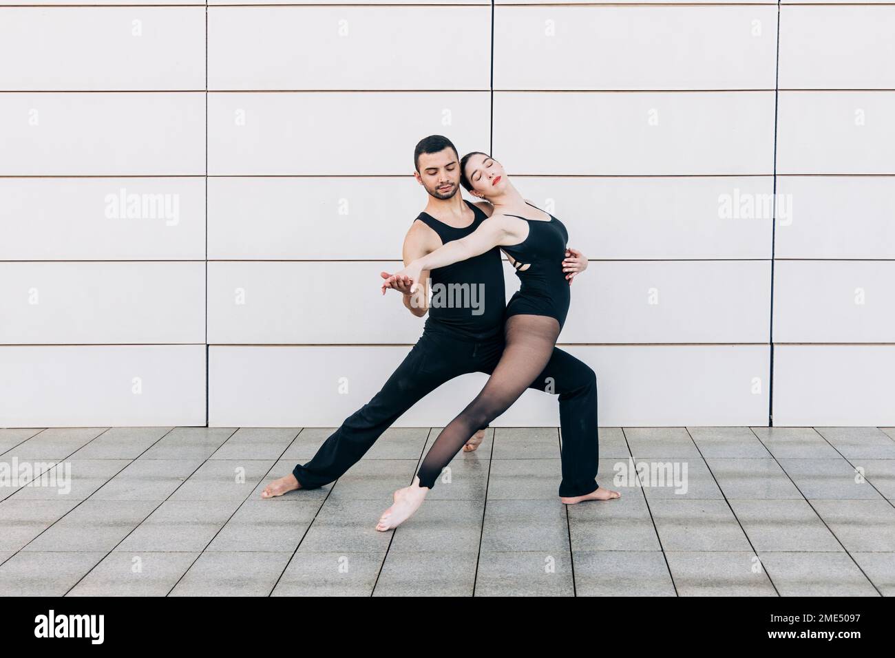 Couple with eyes closed performing dance in front of wall Stock Photo ...