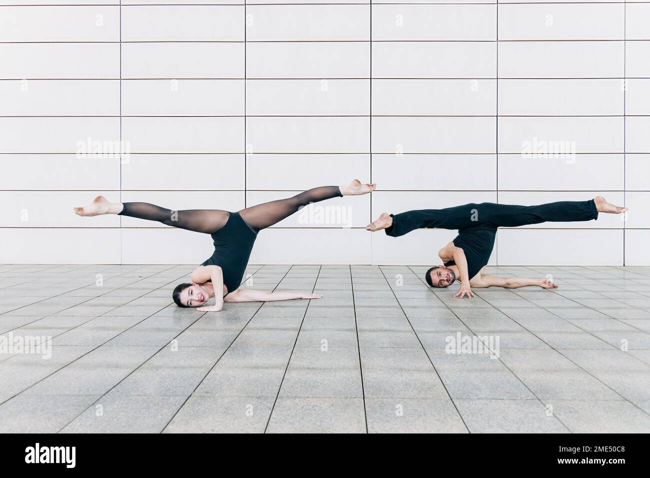 Couple doing splits in front of wall Stock Photo - Alamy