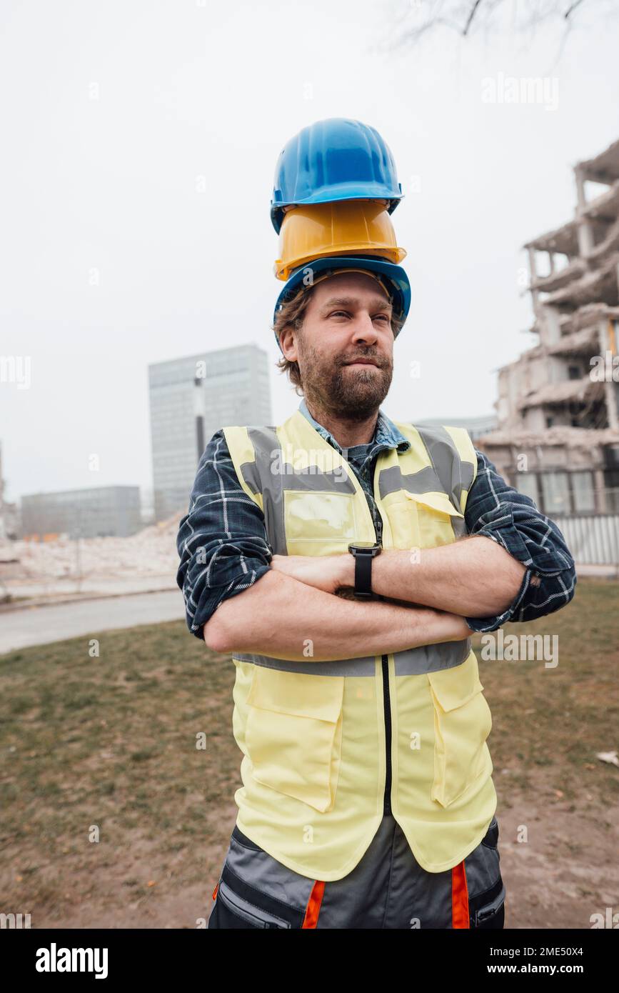 Worker standing with stack of hardhats on head at construction site ...