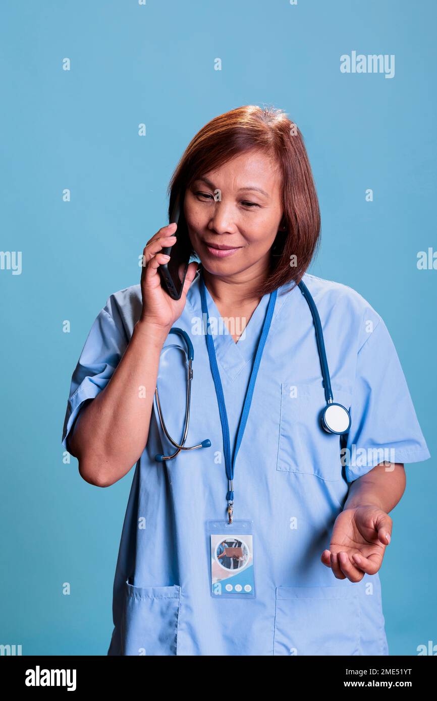 Asian nurse in medical uniform talking at smartphone with remote ...
