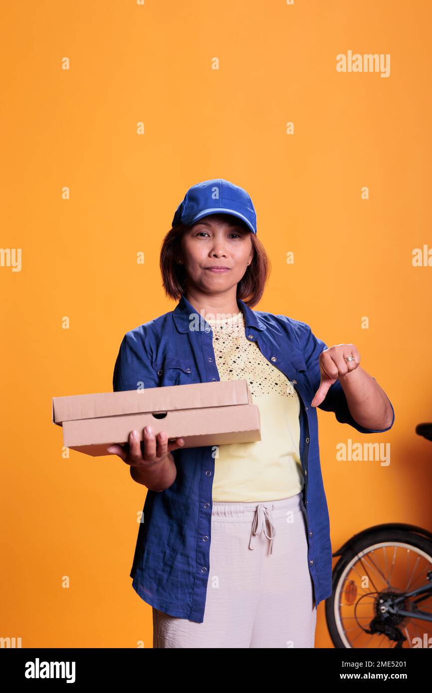 Serious pizzeria delivery worker doing disapproval sign while holding ...