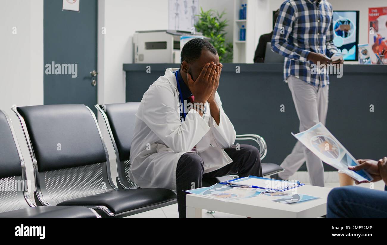 Tired frustrated physician sitting in hospital lobby, feeling ...