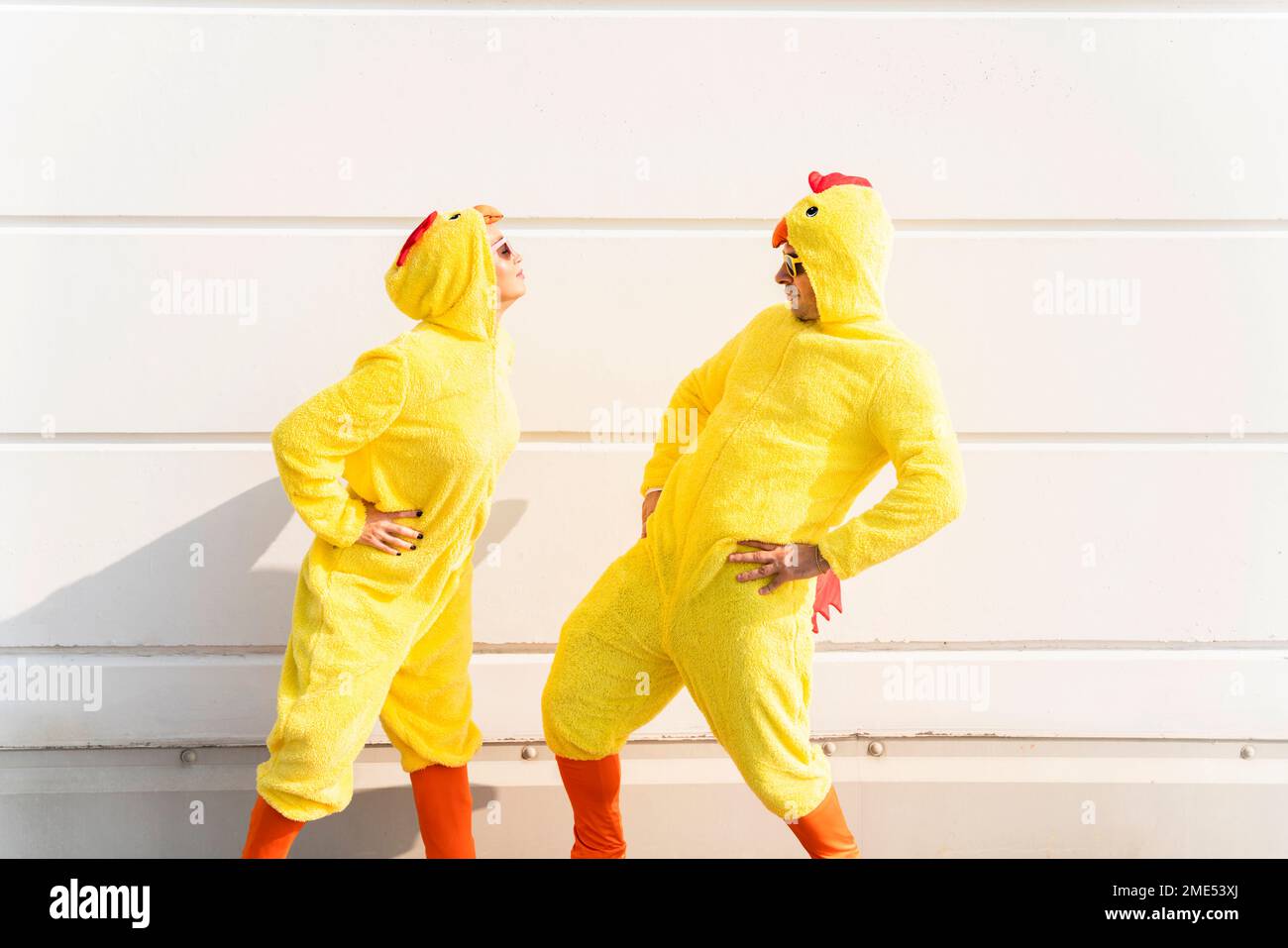 Friends wearing chicken costumes having fun in front of wall Stock ...