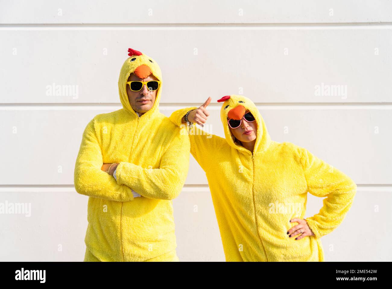 Mature woman gesturing with man wearing chicken costume standing in ...