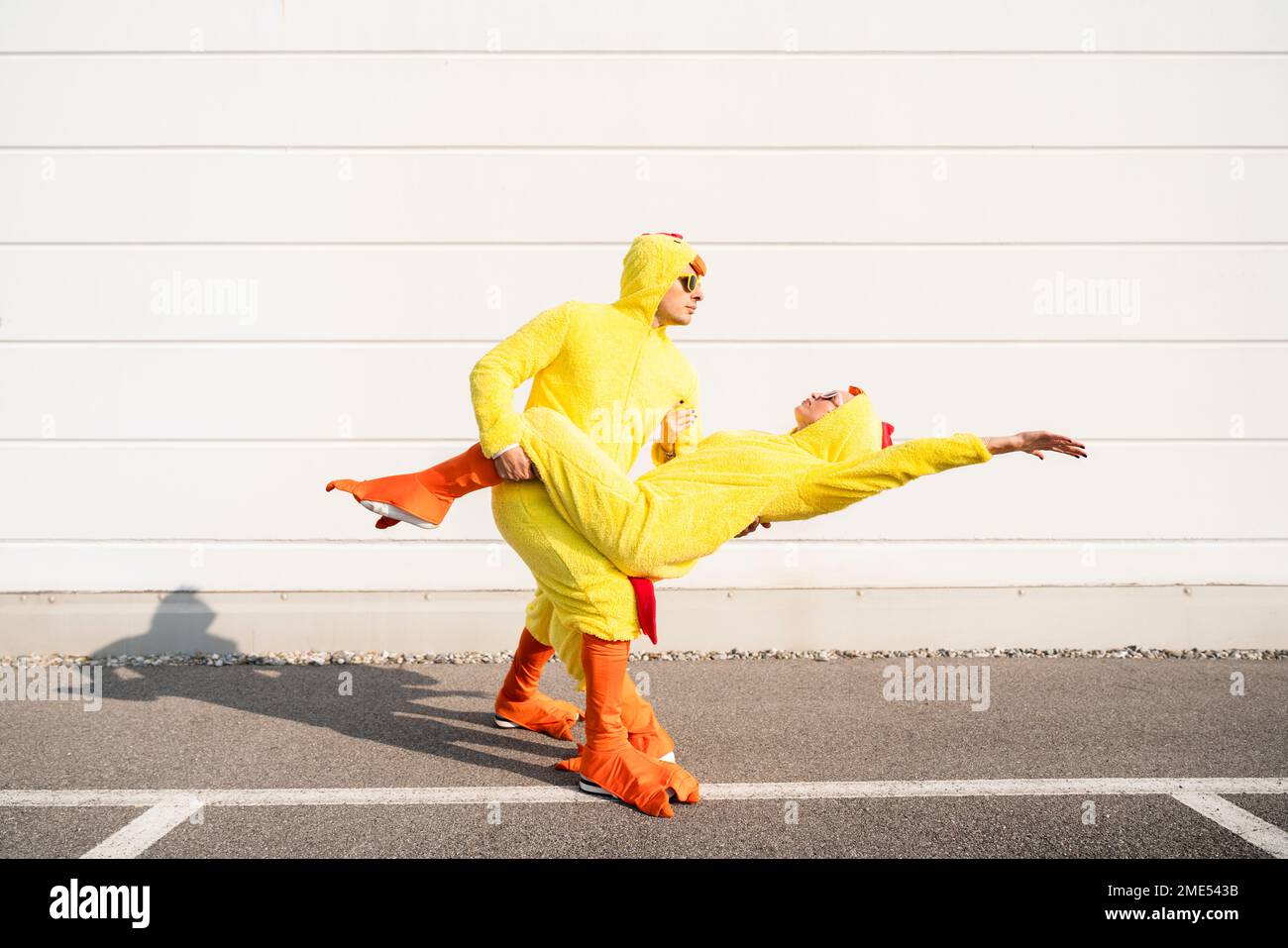 Happy man with woman wearing chicken costumes and dancing in front of ...