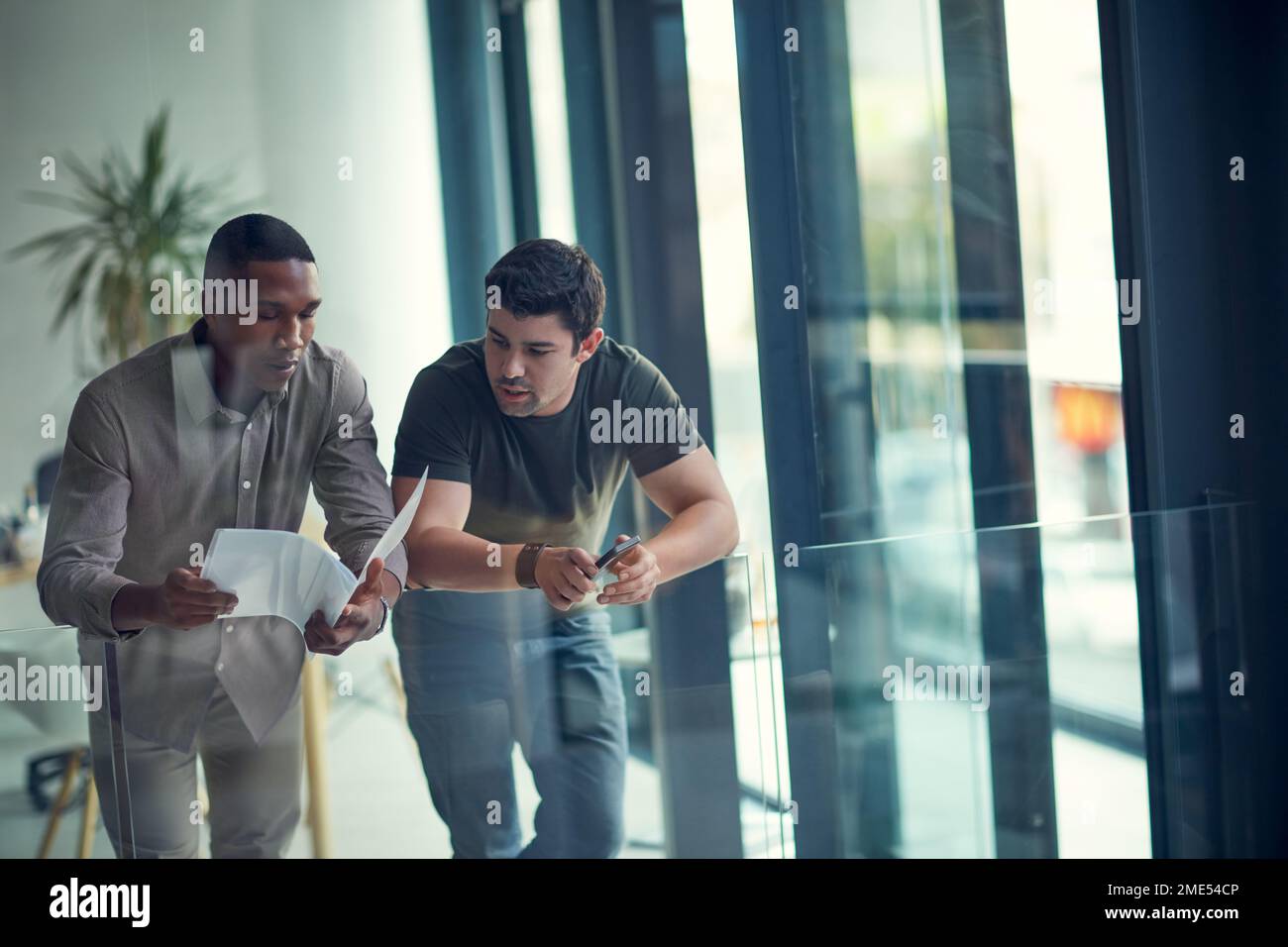 The go getter duo. two young businessmen going over paperwork together ...
