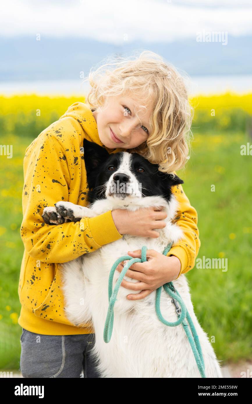 Happy boy stroking and embracing Border Collie dog on field Stock Photo ...