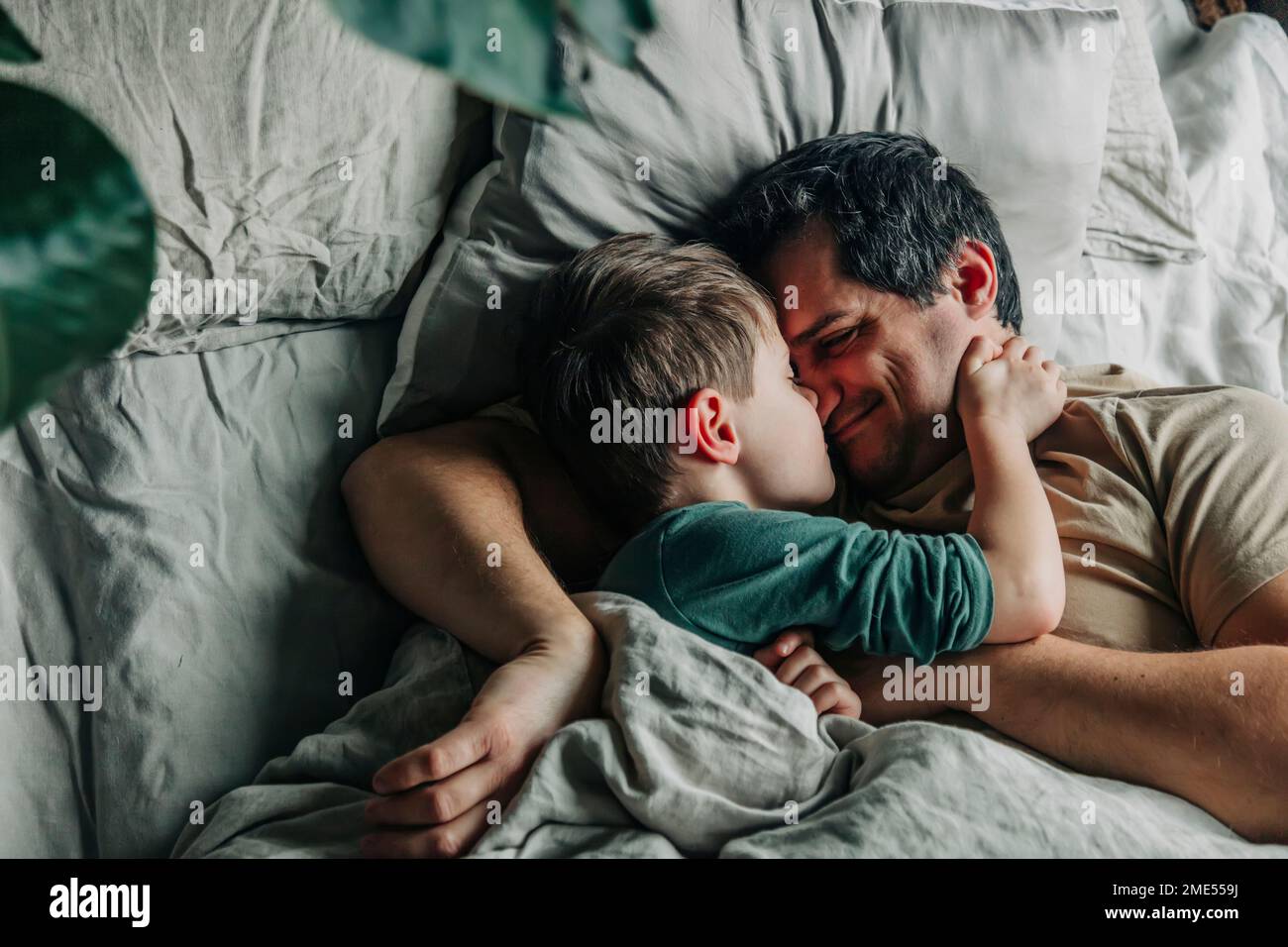 Smiling man with boy sleeping in bed Stock Photo - Alamy