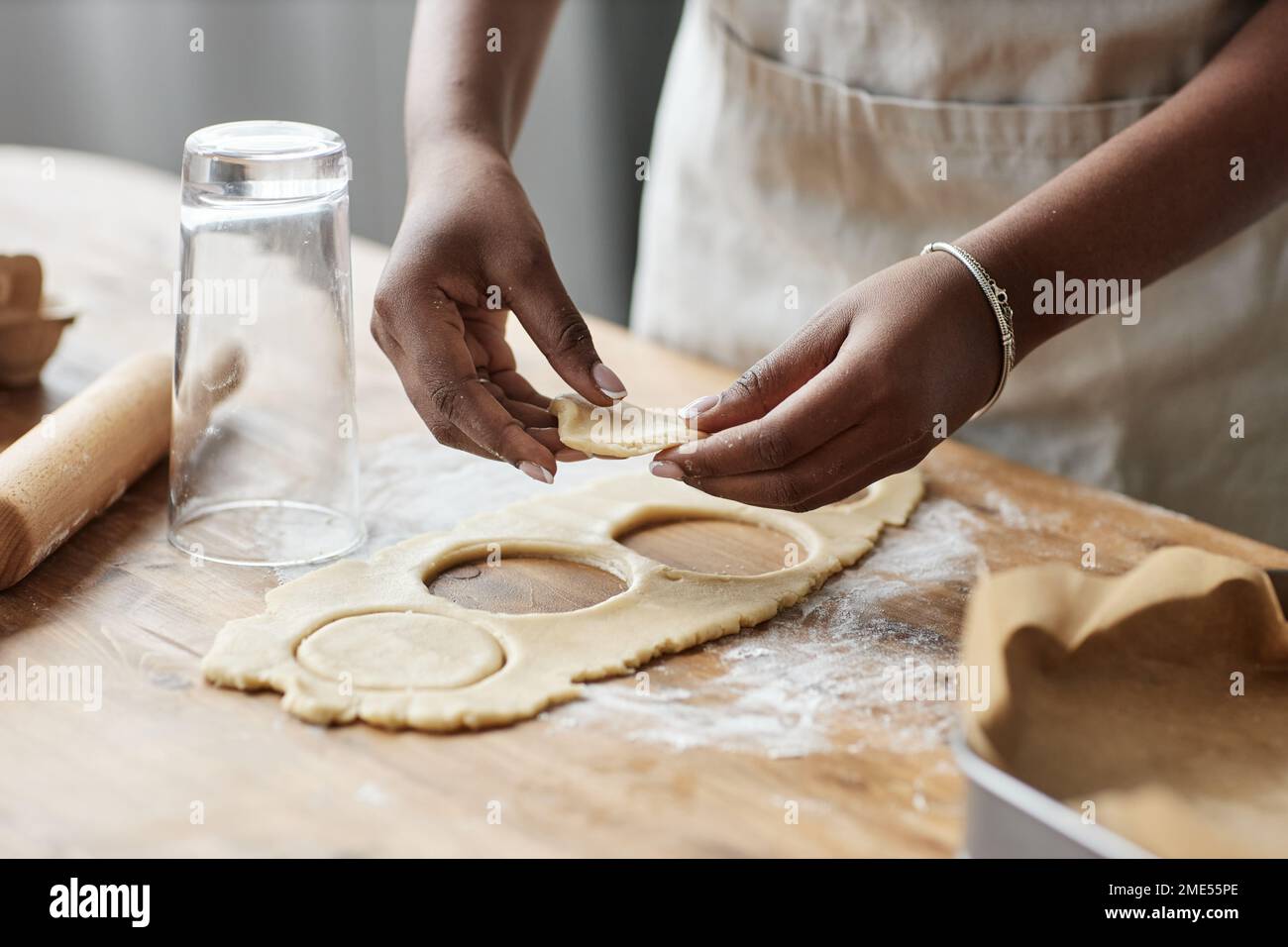 Close up of young black woman baking homemade pastry and cutting cookie ...