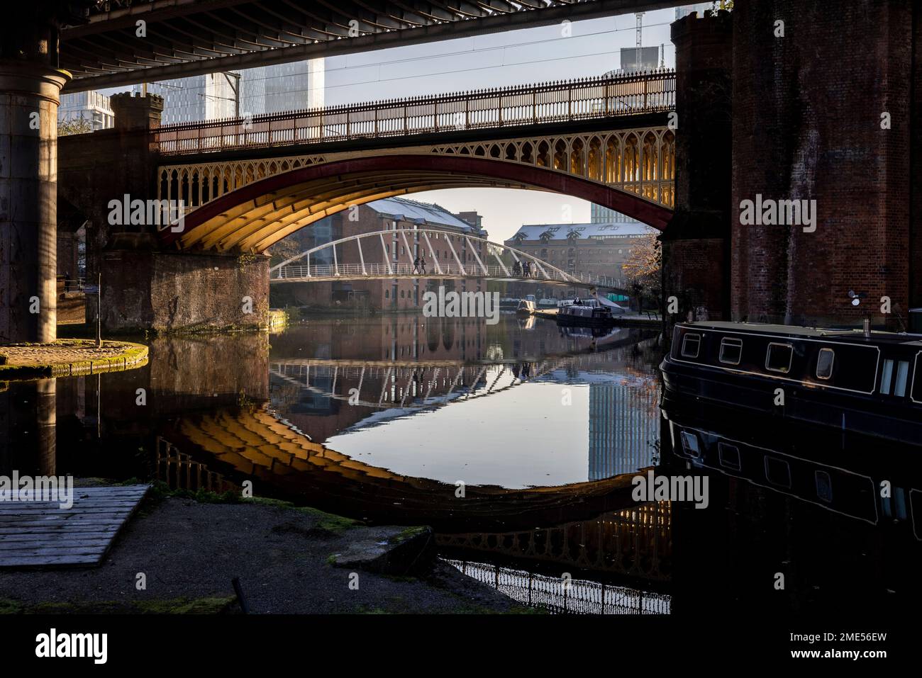 UK, England, Manchester, Arch bridge reflecting on surface of canal ...