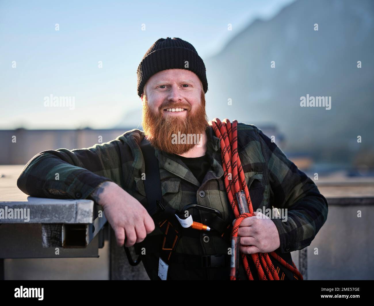 Happy roofer standing with rope at rooftop Stock Photo - Alamy