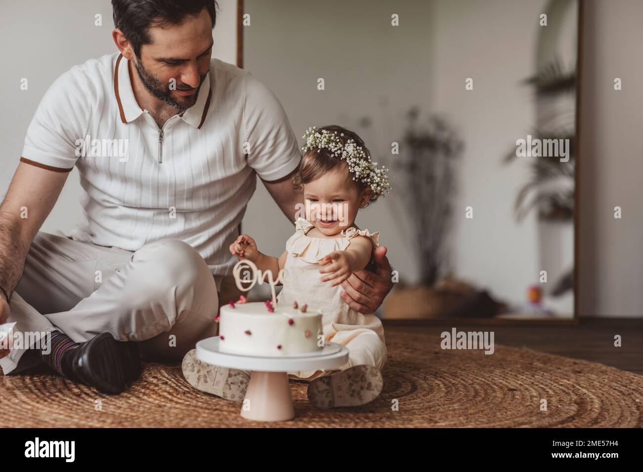 Father sitting with daughter touching birthday cake at home Stock Photo ...