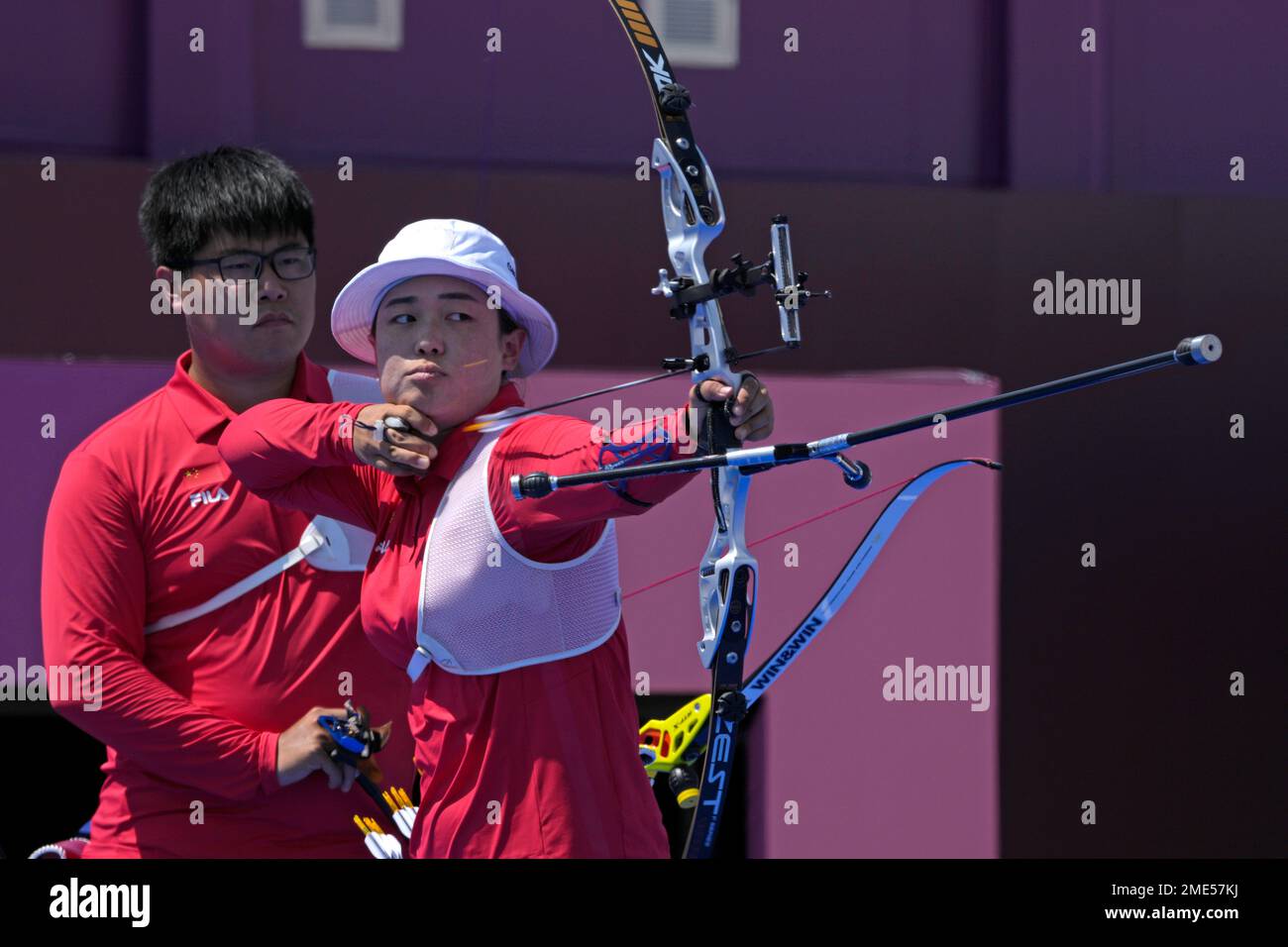 China's Wu Jiaxin, right, releases the arrow flanked by her teammate ...