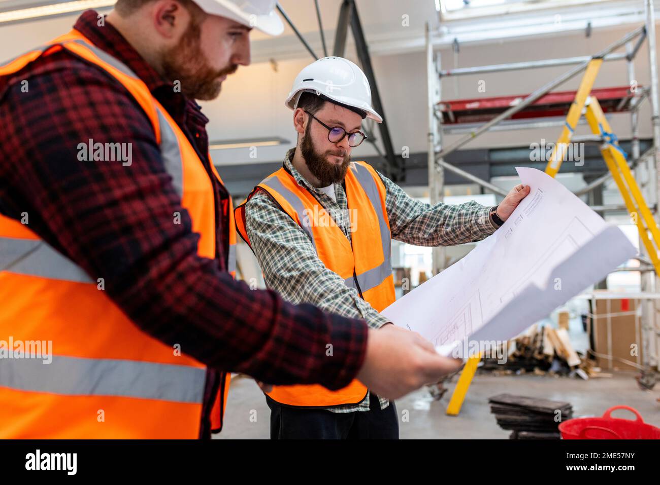 Engineer discussing over blueprint with colleague at construction site ...