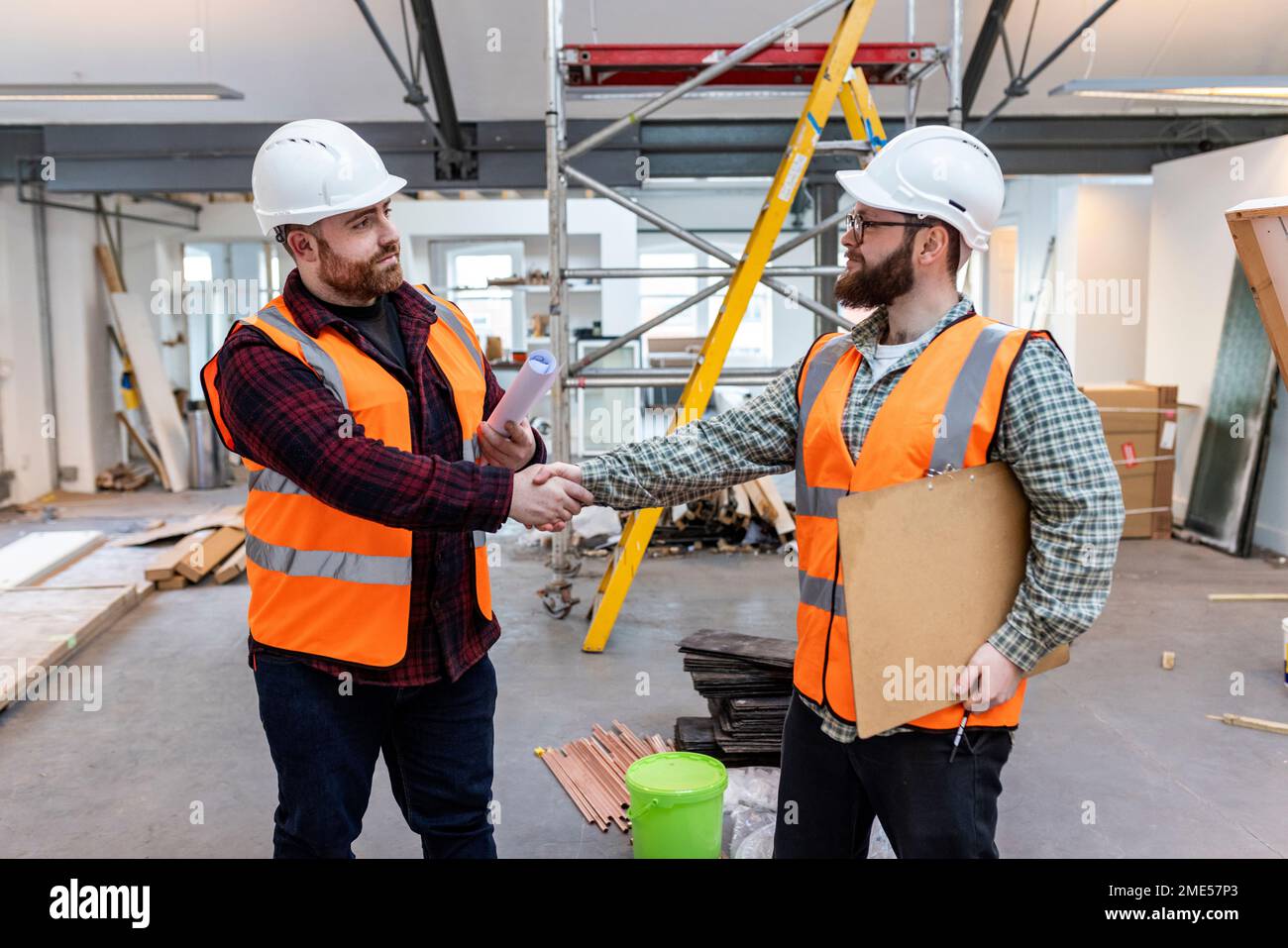 Young engineers shaking hands with each other at construction site ...