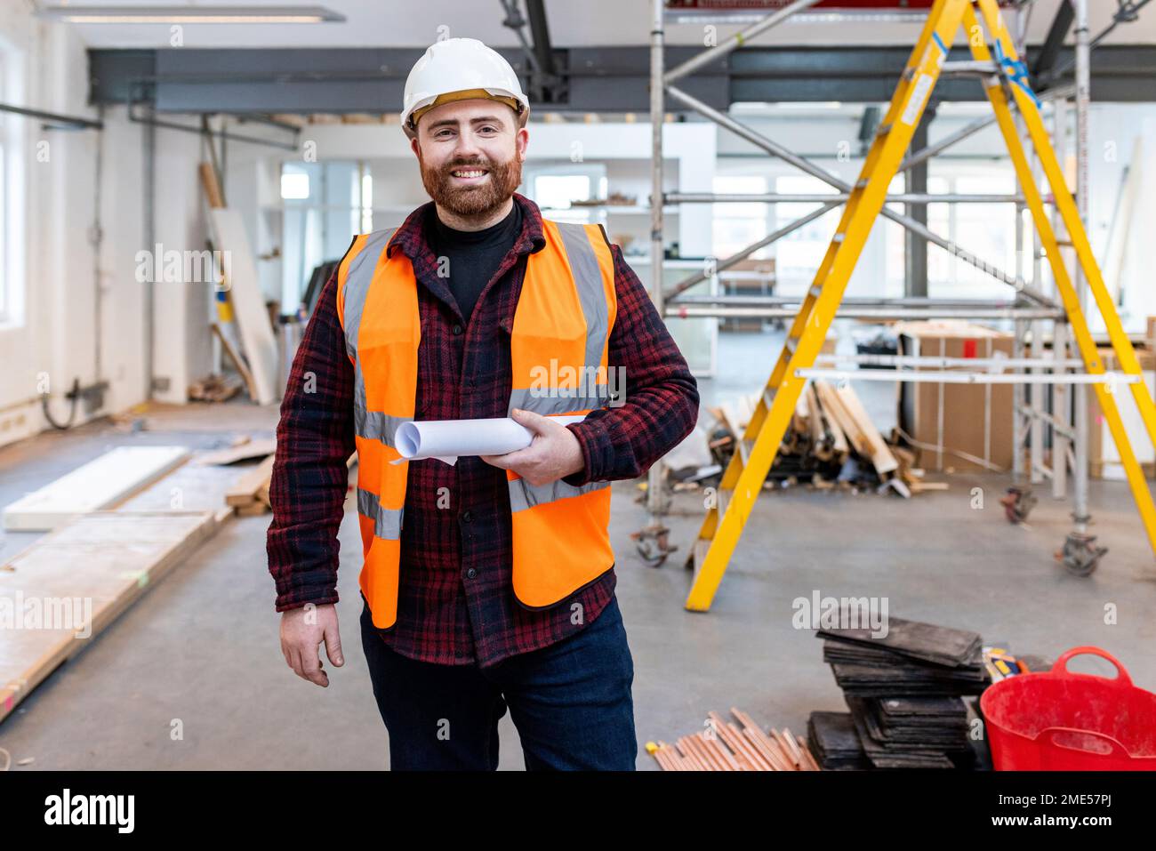 Happy engineer standing with rolled document at construction site Stock ...