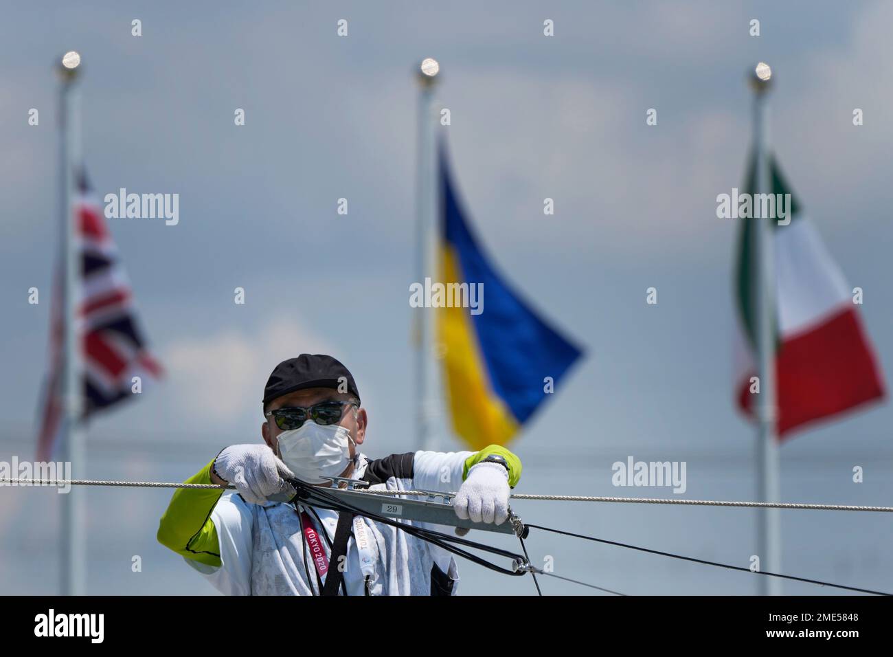 An official wears a mask and gloves as he prepares the cables for the ...