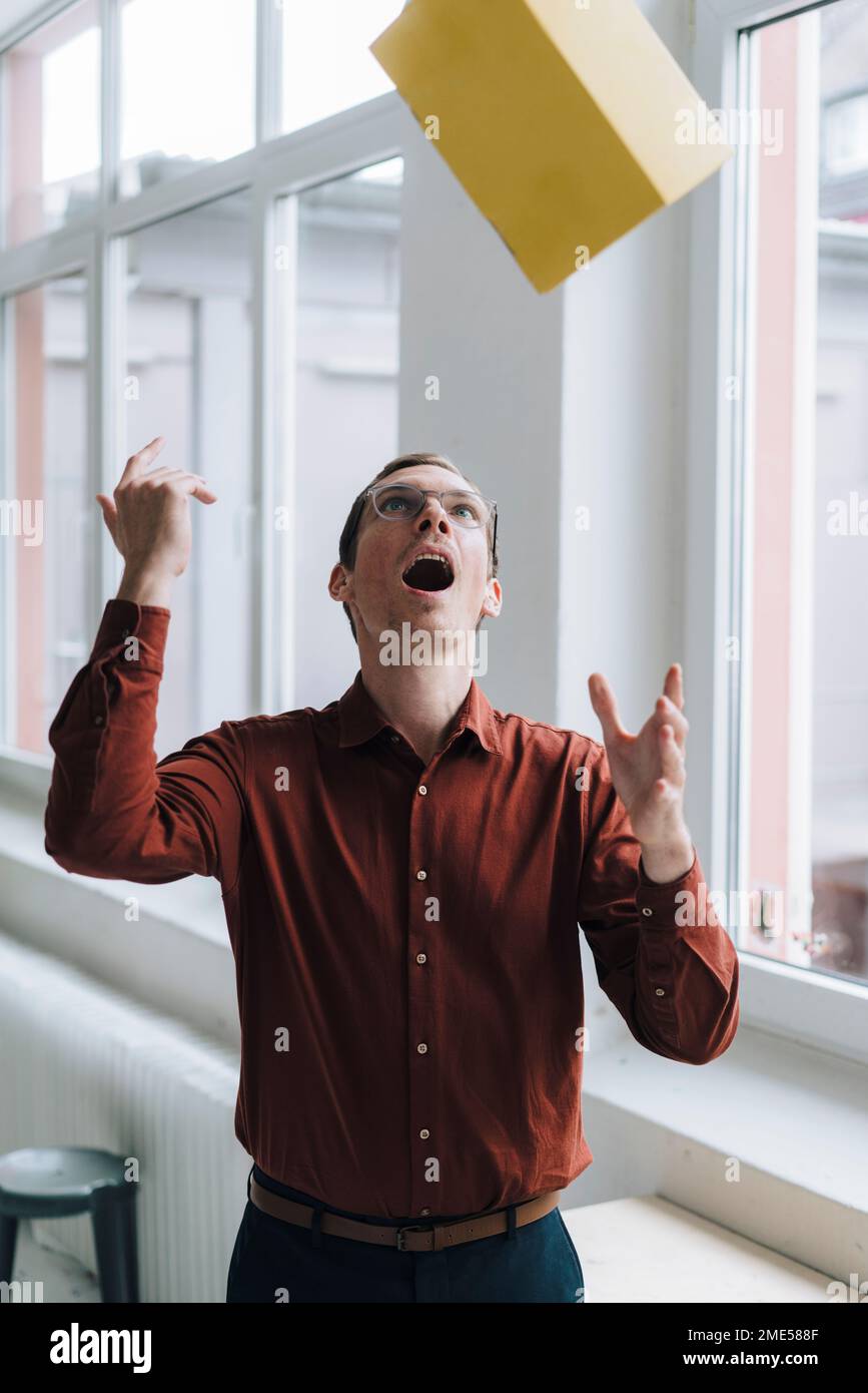 Surprised businessman throwing box standing in front of window Stock ...