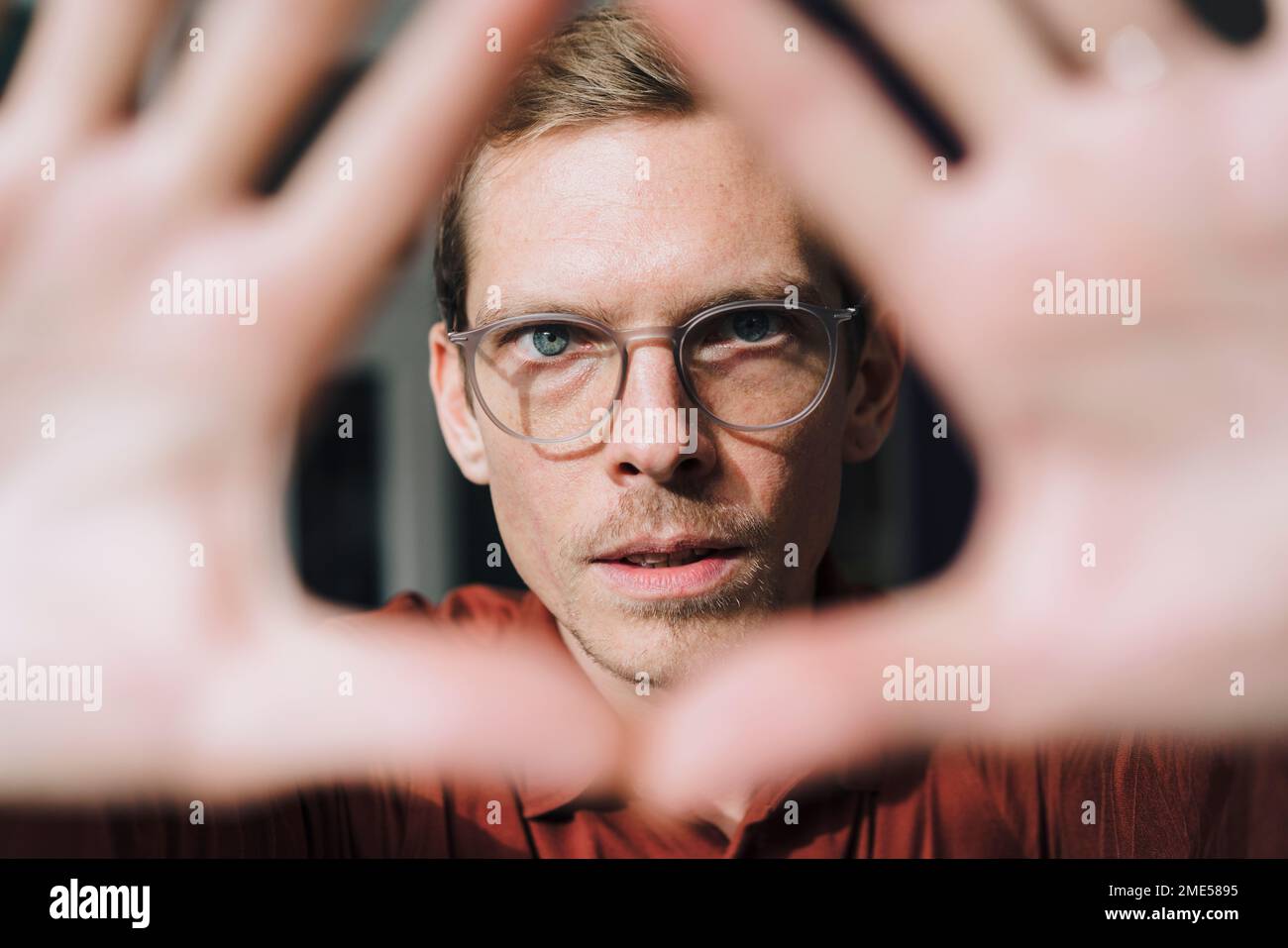 Businessman wearing eyeglasses looking through finger frame Stock Photo ...