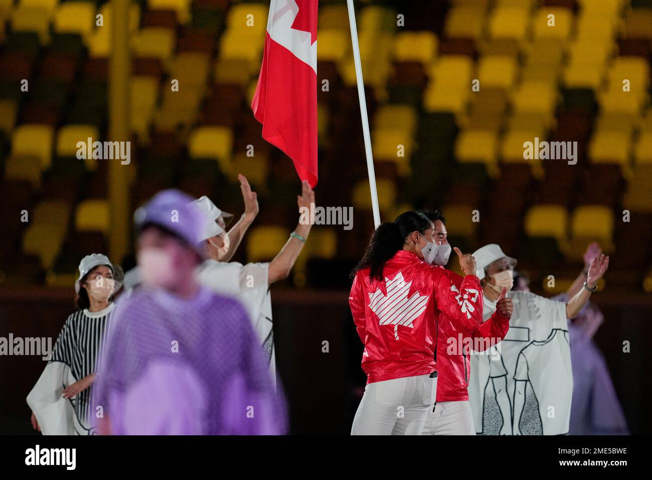 Miranda Ayim and Nathan Hirayama, of Canada, carry their country's flag ...
