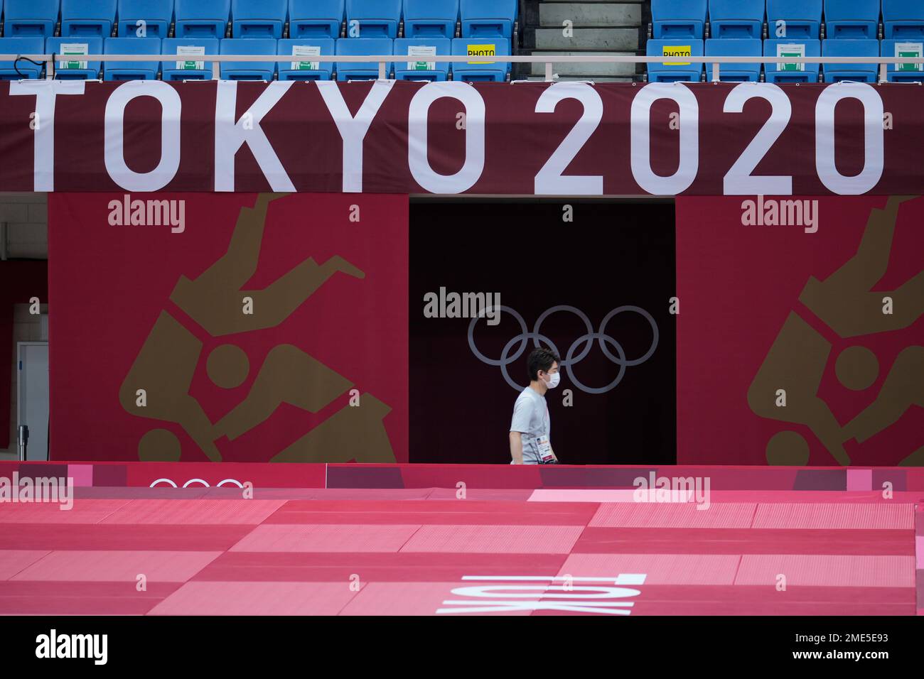 A worker walks under the Tokyo 2020 logo on the field of play for judo ...