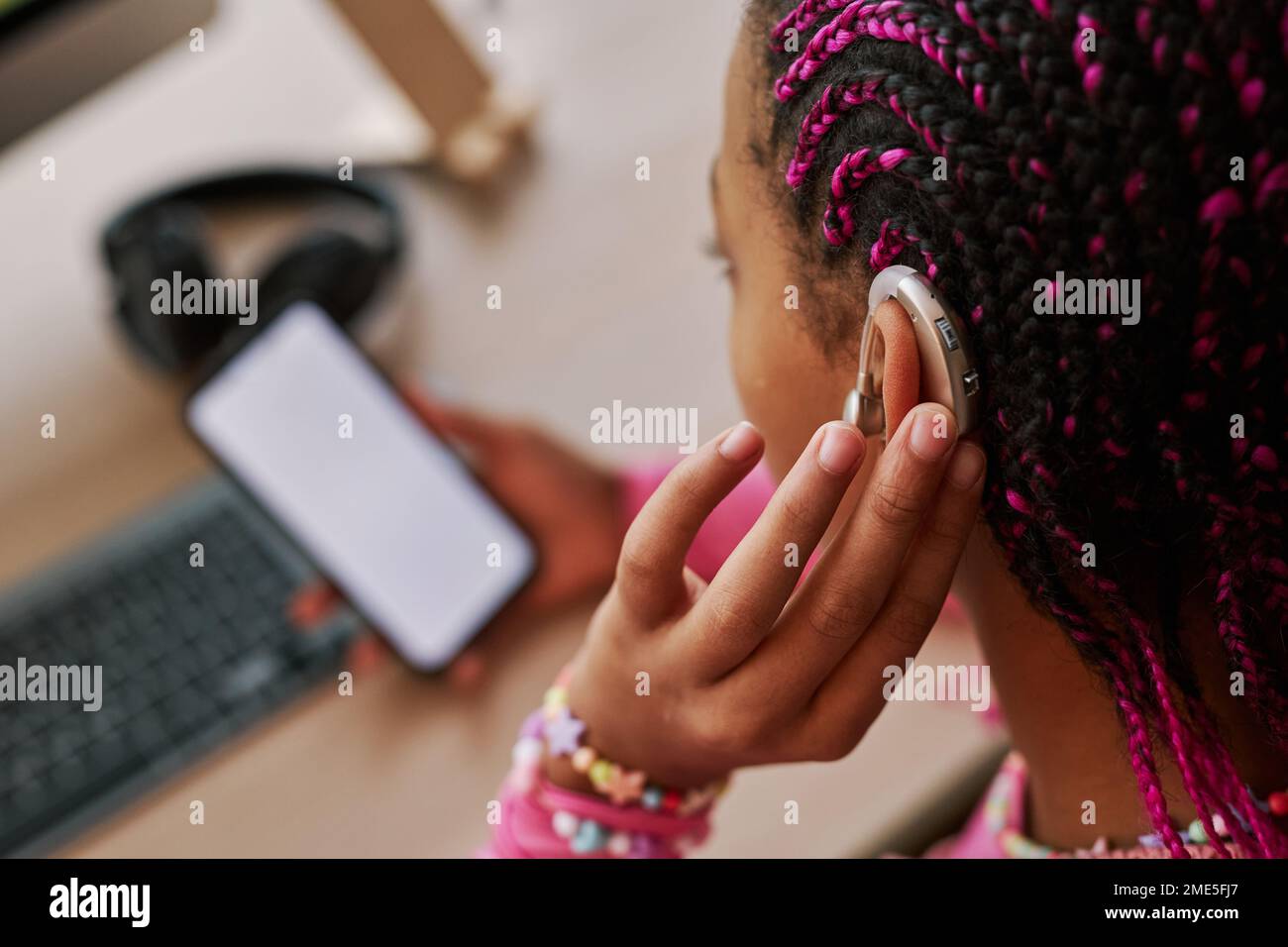 Close up of black teenage girl wearing hearing aid on ear and pressing ...