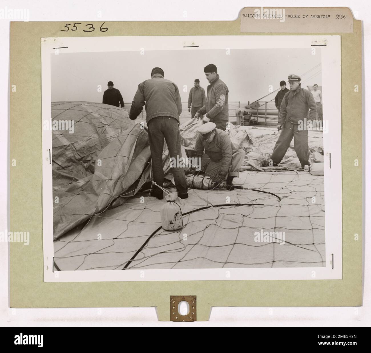 Coast Guardsmen inflate a captive balloon, which is used to support the ...