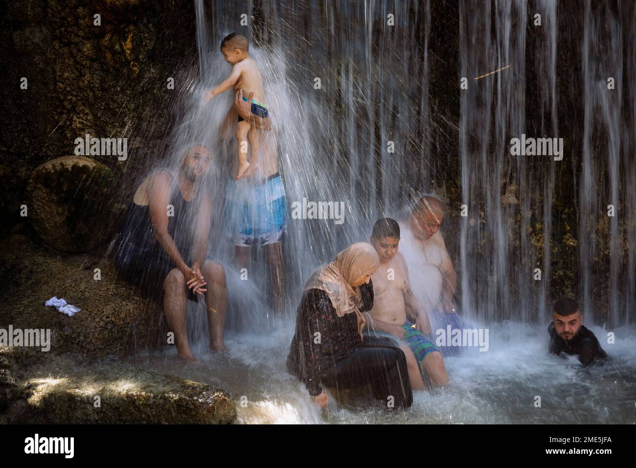Israeli Arabs stand under a waterfall during the Muslim Eid al-Adha ...