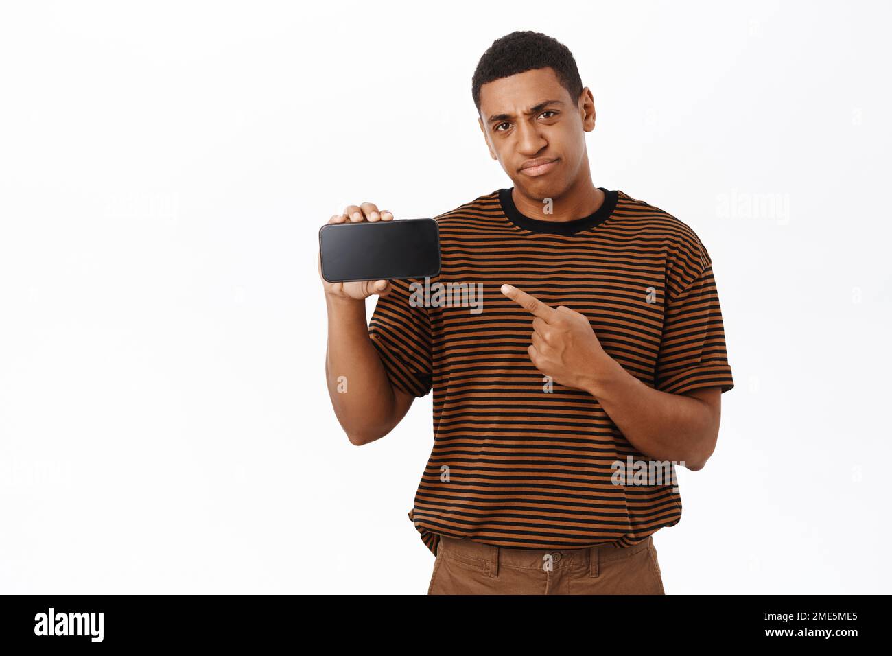 Man with disappointed face pointing, showing mobile phone screen ...