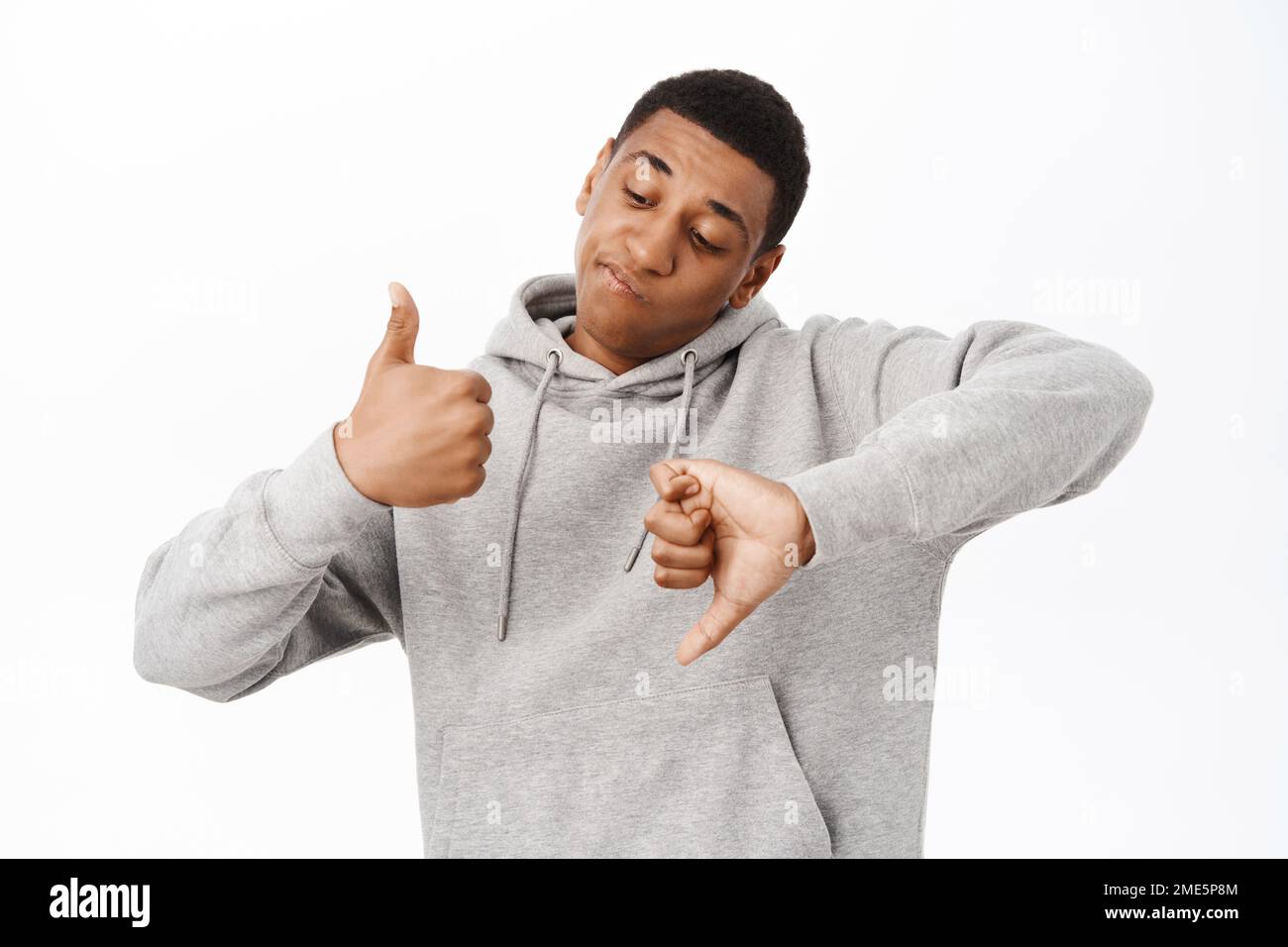 Yes or no. Puzzled african american man shows thumbs up and thumbs down ...