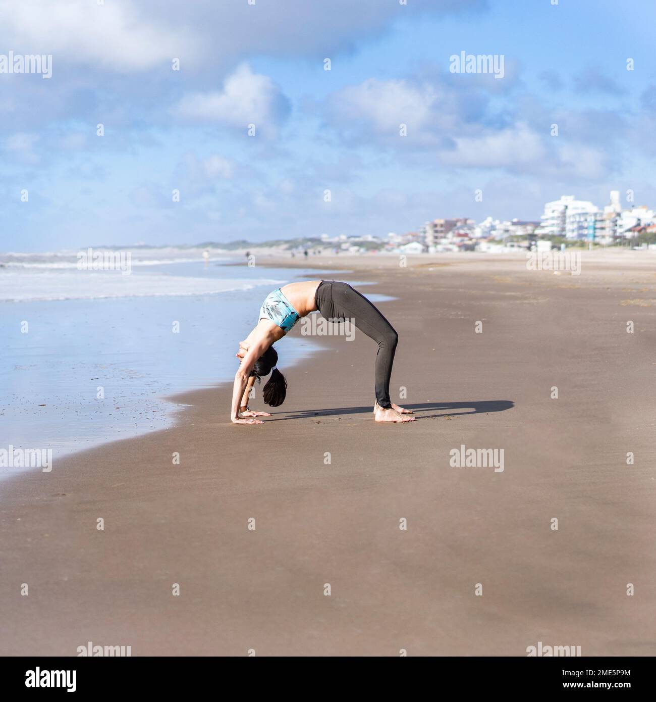 A Woman Practicing Yoga On The Water At The Beach Doing Wheel Urdhva