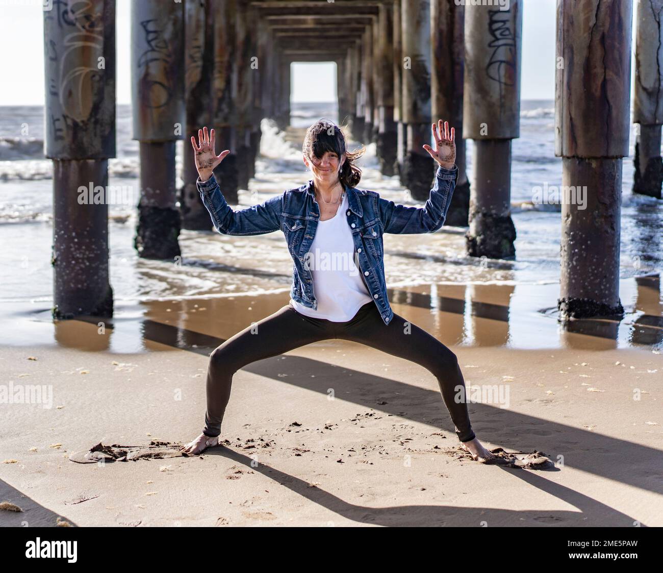 A woman practicing yoga outdoors, doing Goddess with Cactus Arms ...