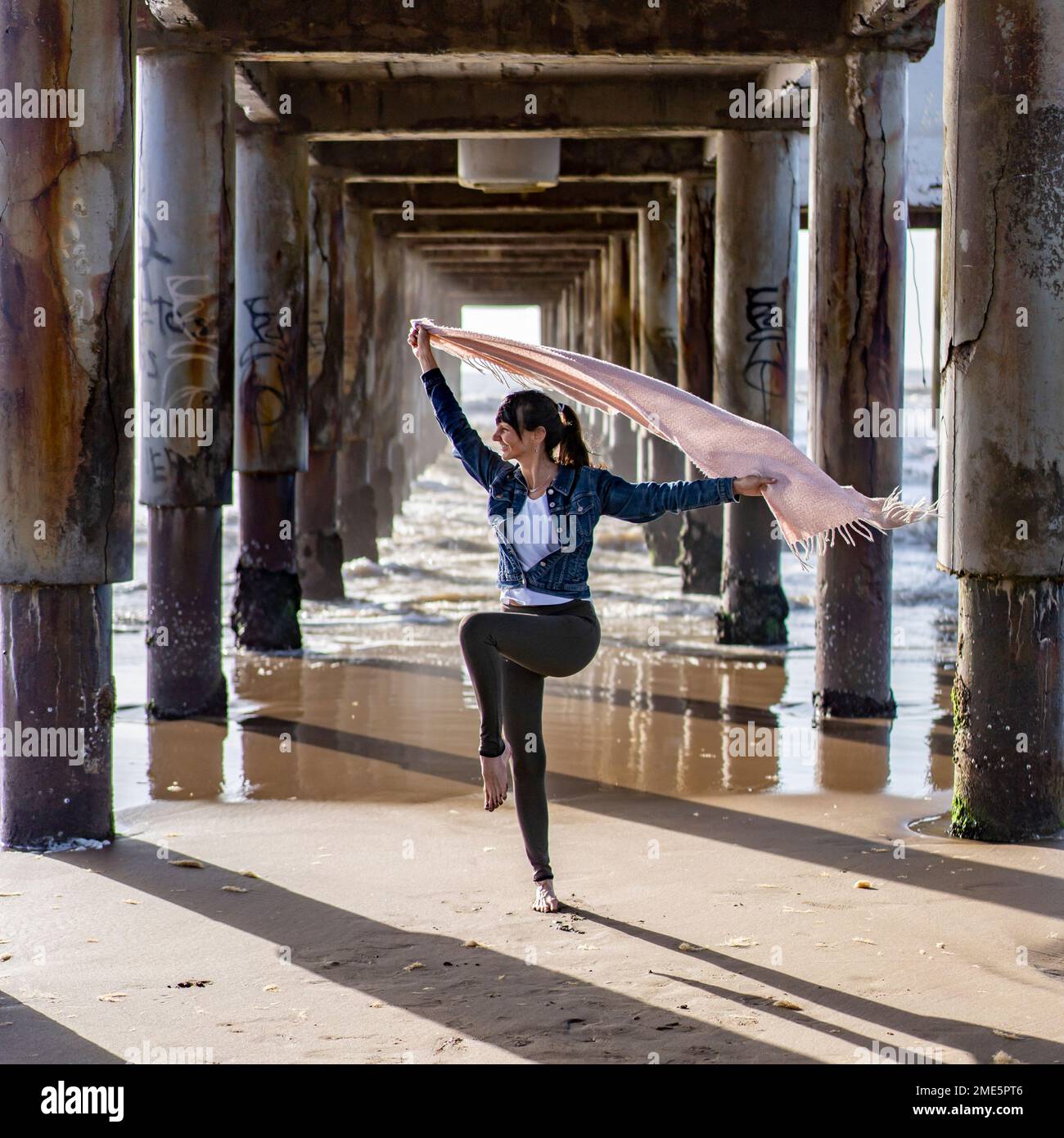Woman dancing under a pier holding a scarf on the wind Stock Photo - Alamy