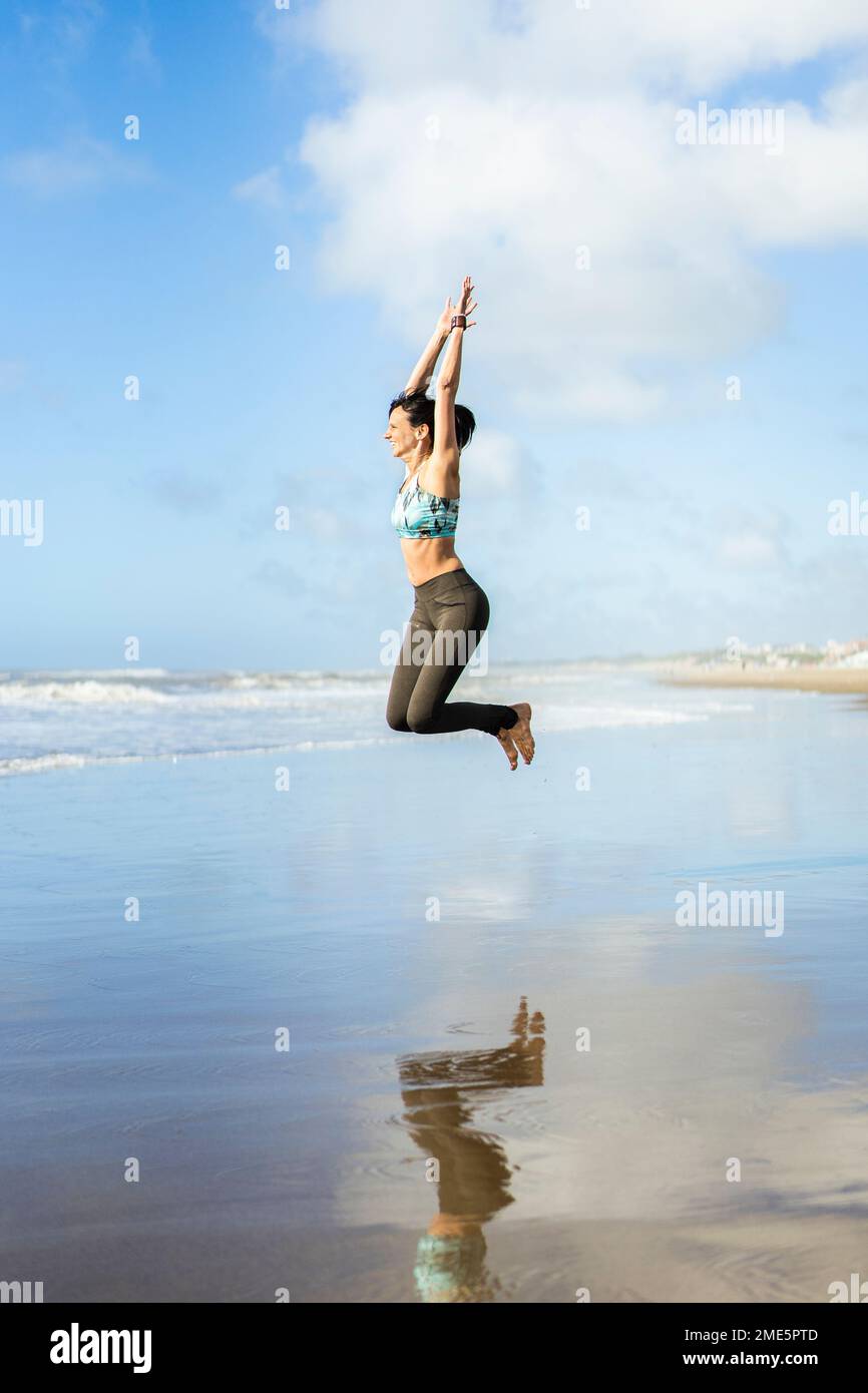 Woman jumping at the beach while reflected in the water Stock Photo - Alamy