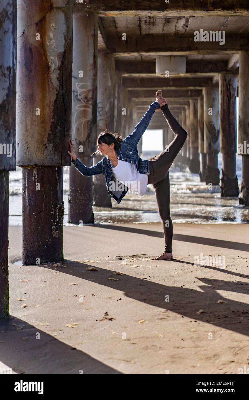 A woman practicing yoga outdoors, doing Standing Bow pose Stock Photo ...
