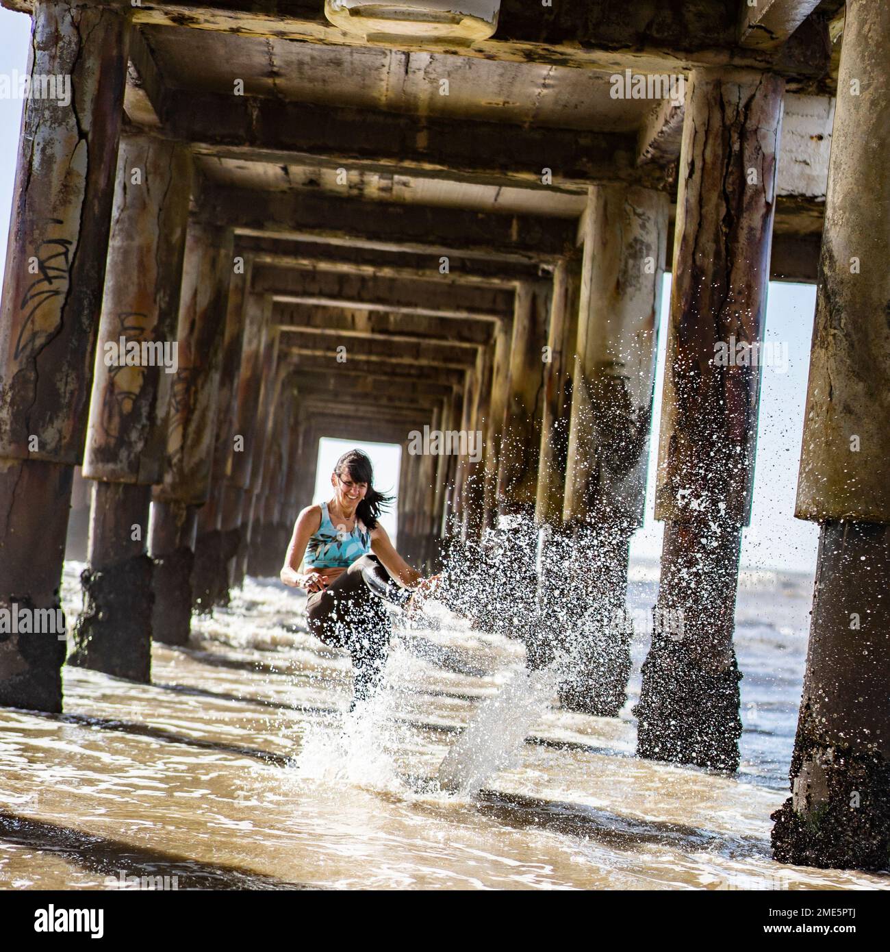 Happy woman splashing under a pier at the beach Stock Photo - Alamy