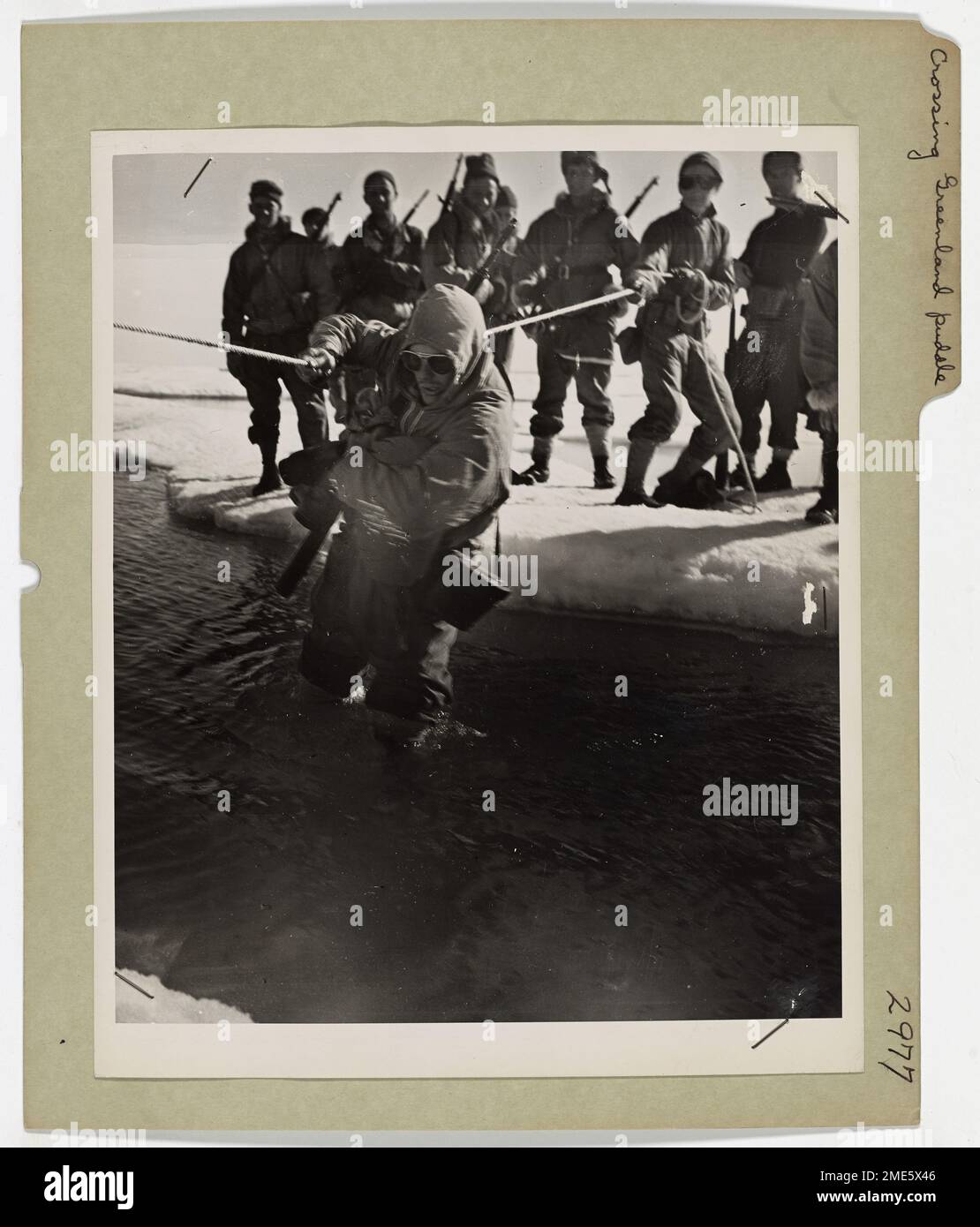 This image shows Coast Guardsmen crossing a melted ice puddle in ...