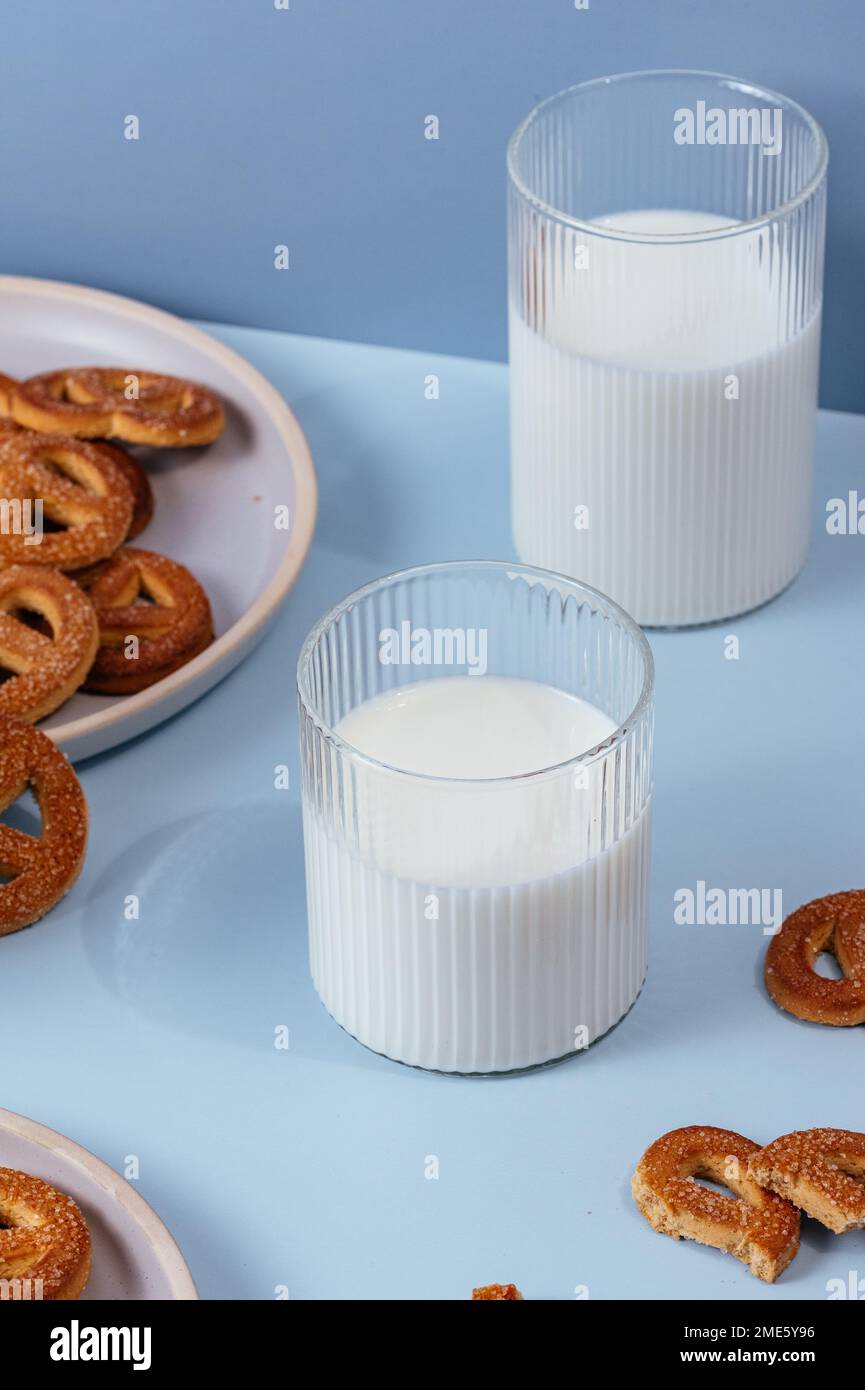 Milk in a glass and a bottle, cookies in a plate. Light blue bac Stock ...