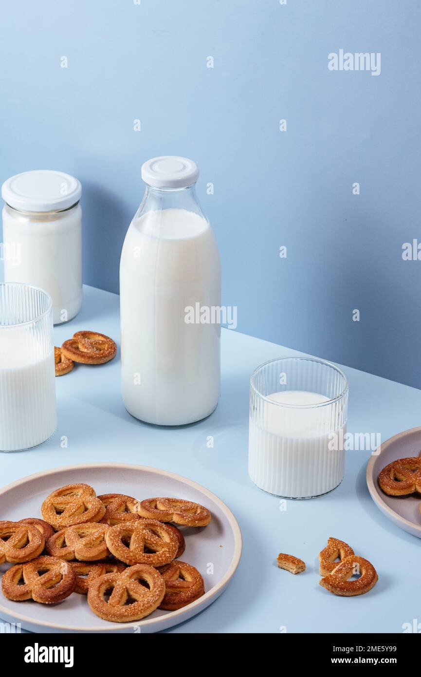 Milk in a glass and a bottle, cookies in a plate. Light blue bac Stock ...