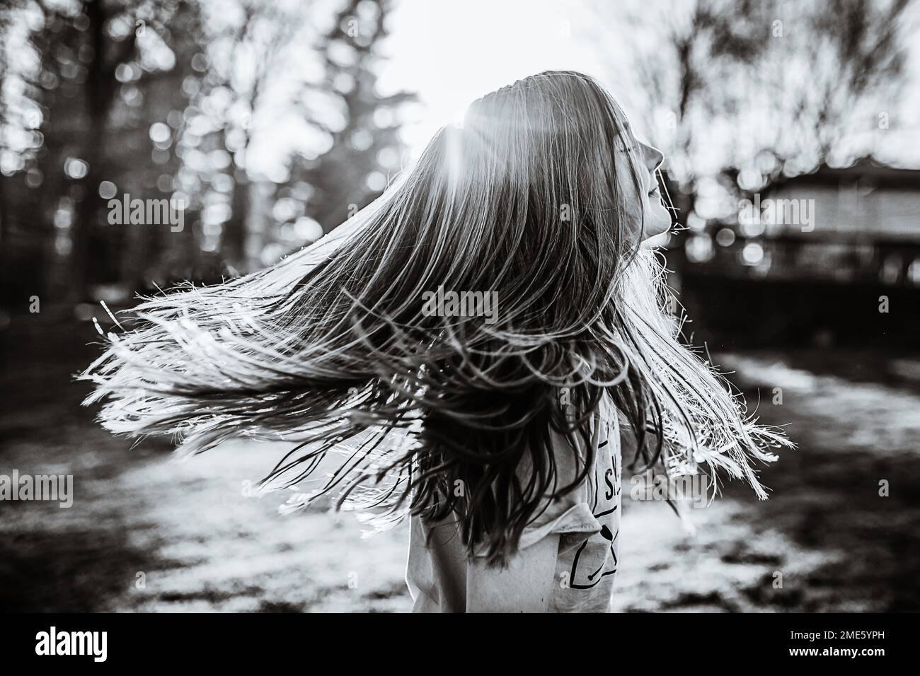 Young girl swinging long hair in backlight Stock Photo - Alamy