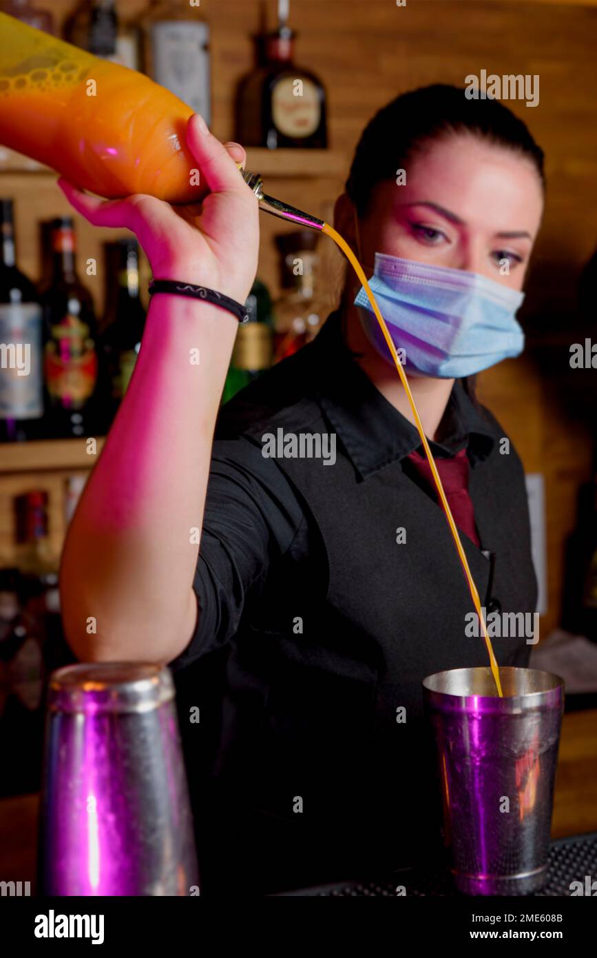 young girl with mask working as a bartender, preparing cocktail ...