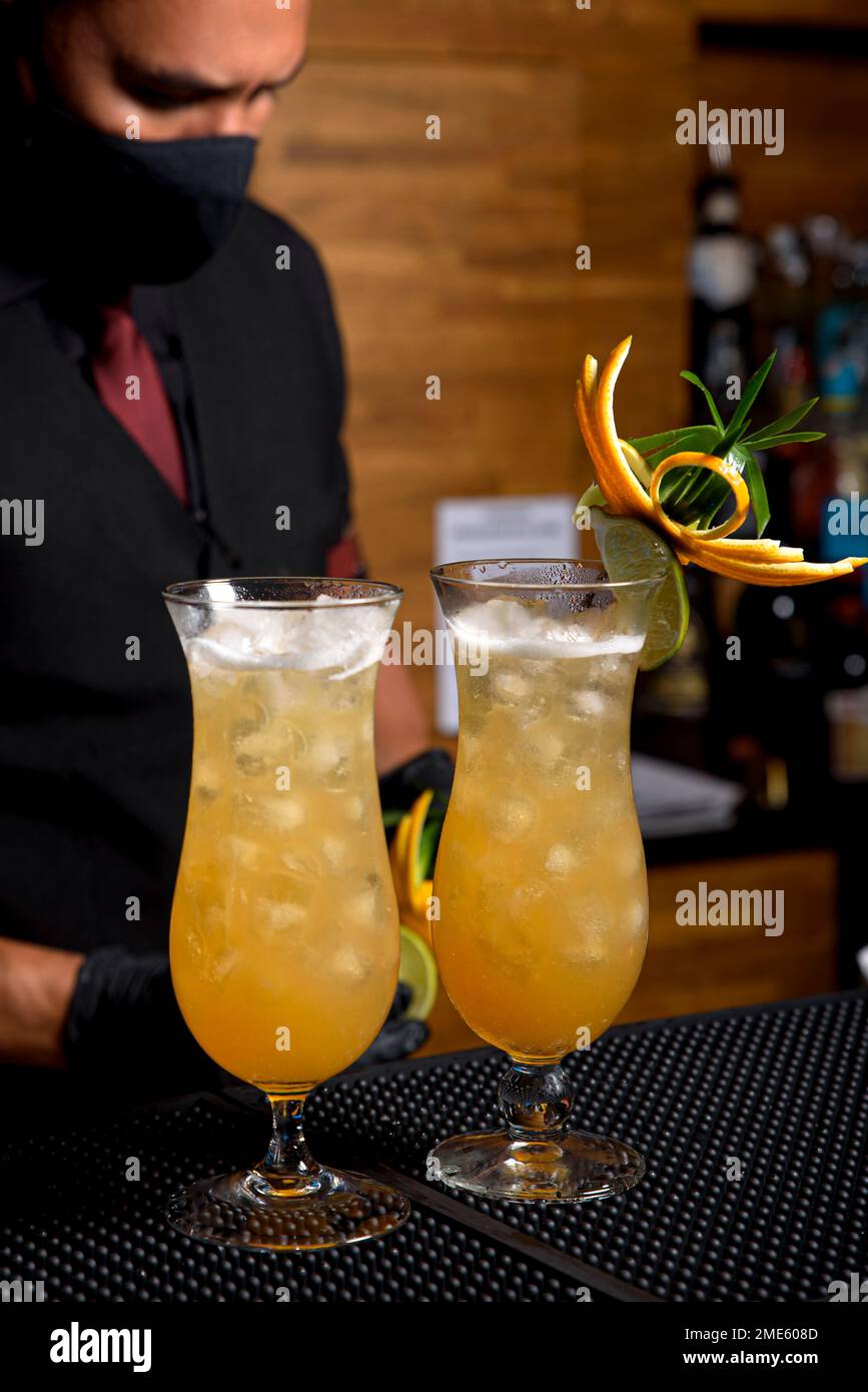 Young professional bartender is preparing cocktail for his clients at ...