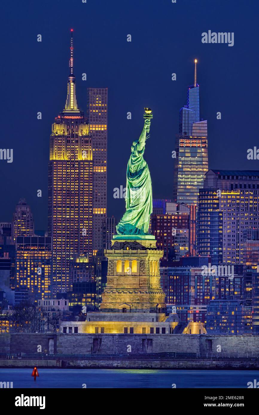 Statue of Libery in the foreground with the New York city skyline in ...