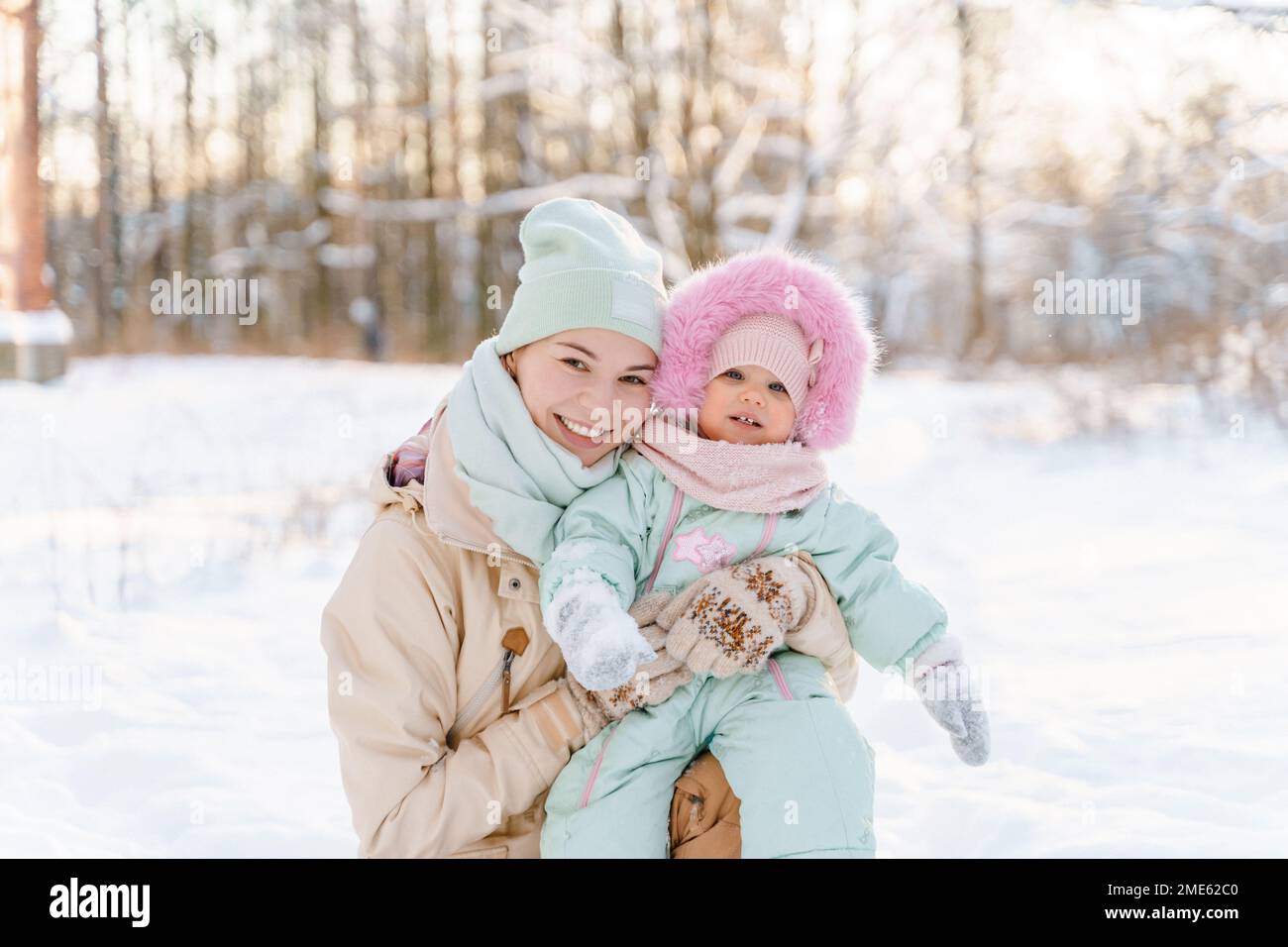 Portrait of a cute ruddy baby toddler girl in a warm mint-colored downy ...