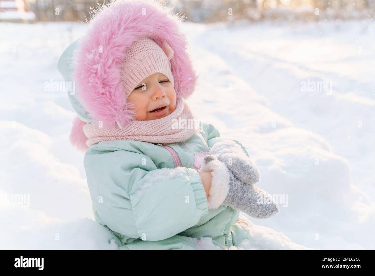 Close-up portrait of a cute ruddy baby girl in a warm mint-colored ...