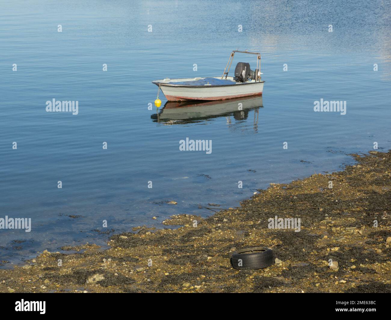 A beach with a boat and pollution from wheels thrown into the sea in ...