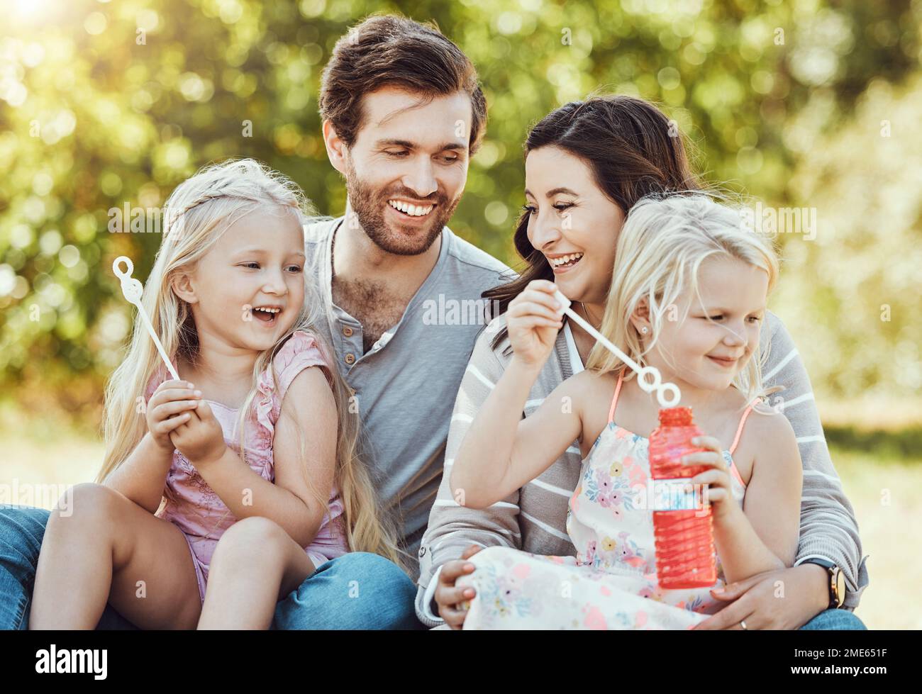 Family, bubbles and park fun outdoor feeling happiness, love and parent ...