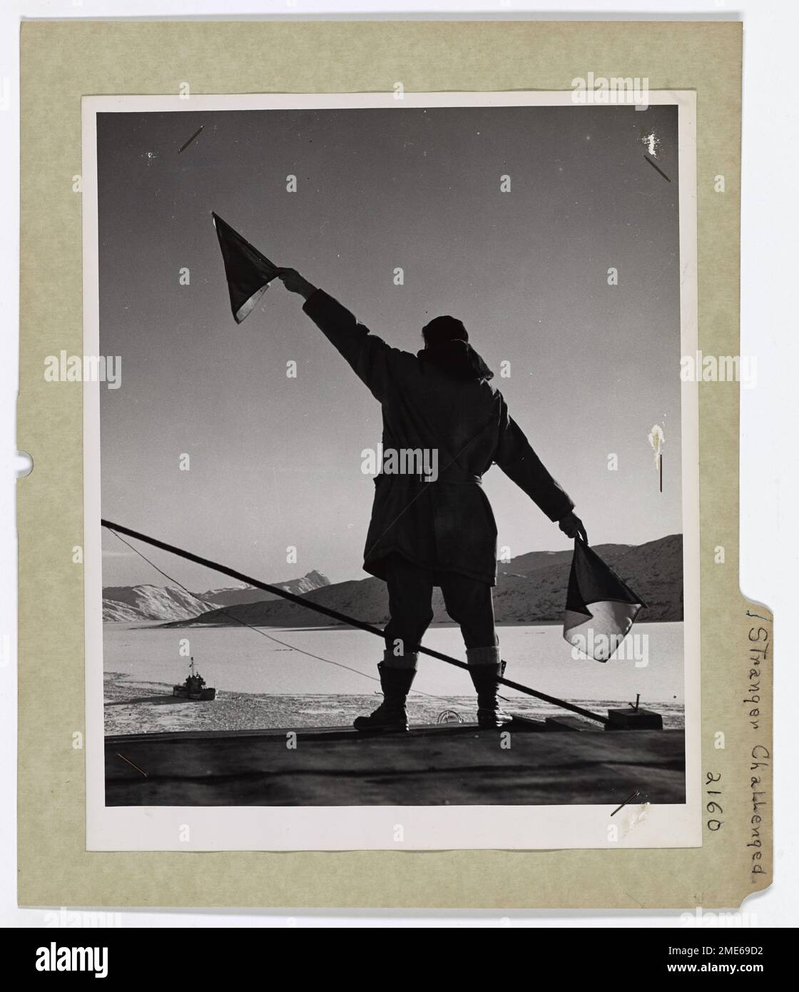 A Coast Guard signalman flags a challenge to a strange vessel ...